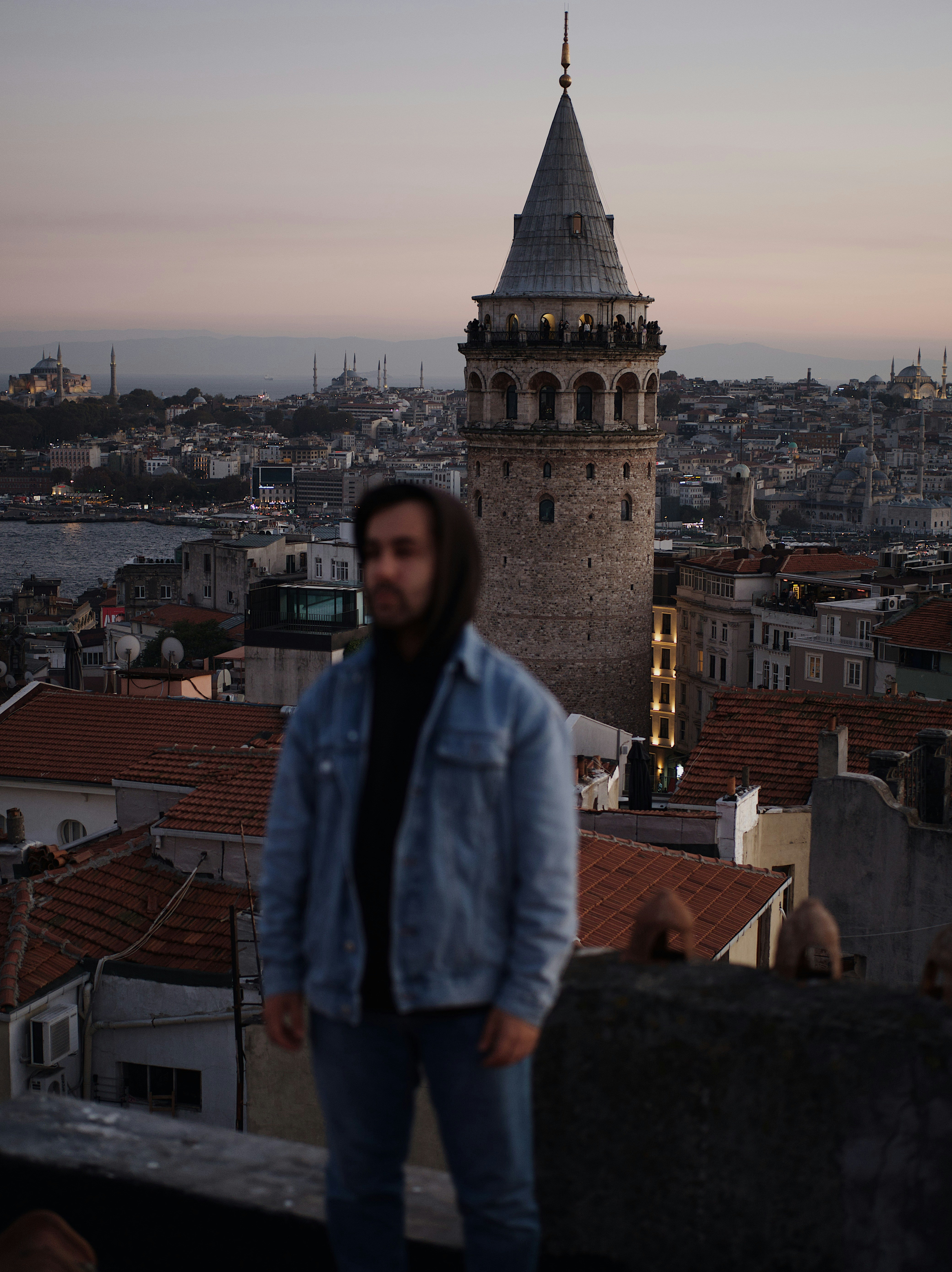 Galata Tower at Dusk: Cityscape Framed by a Blurred Foreground Figure