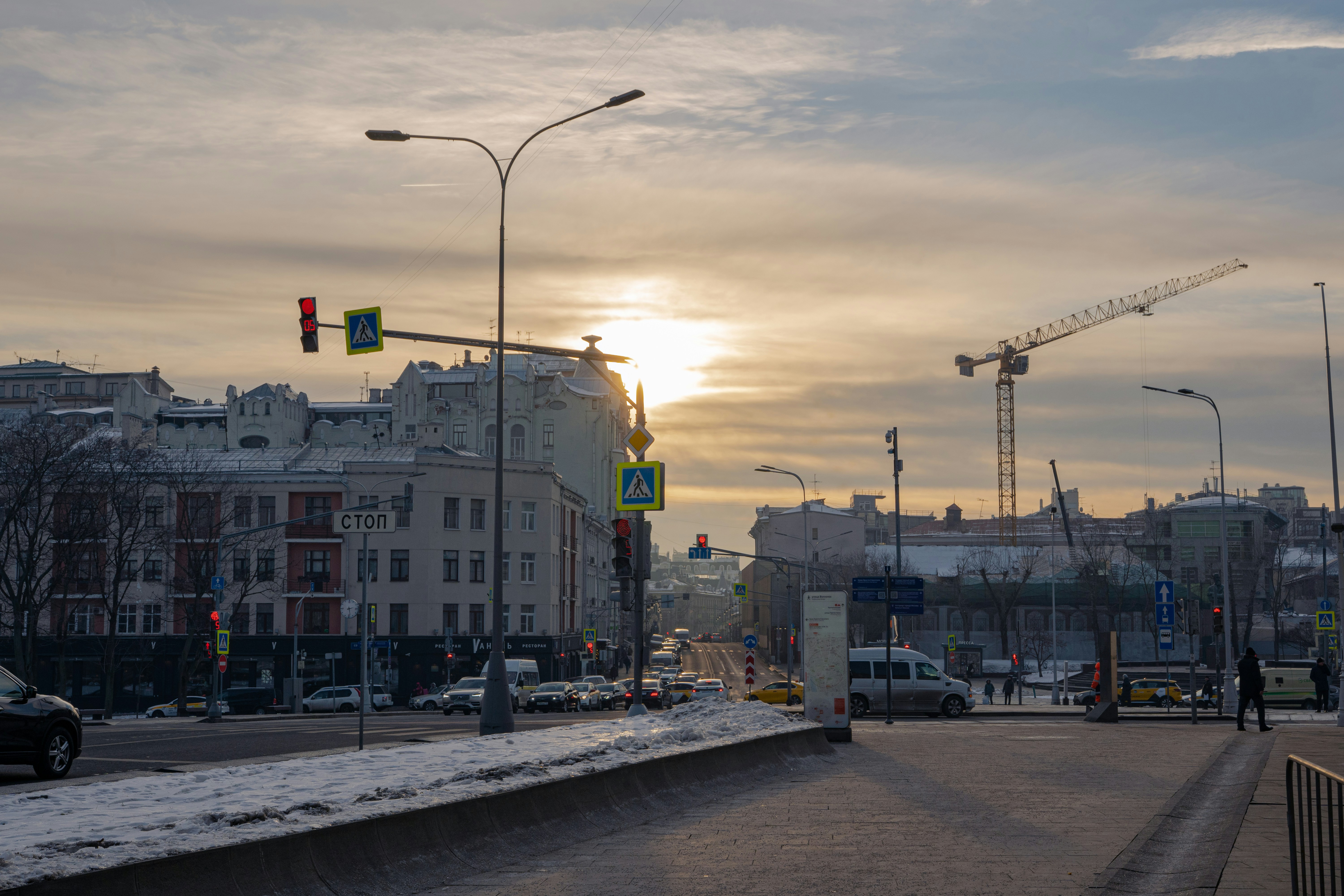 Dusk on the Snowy Boulevard: Crane, Crosswalks, and the Fading Sun
