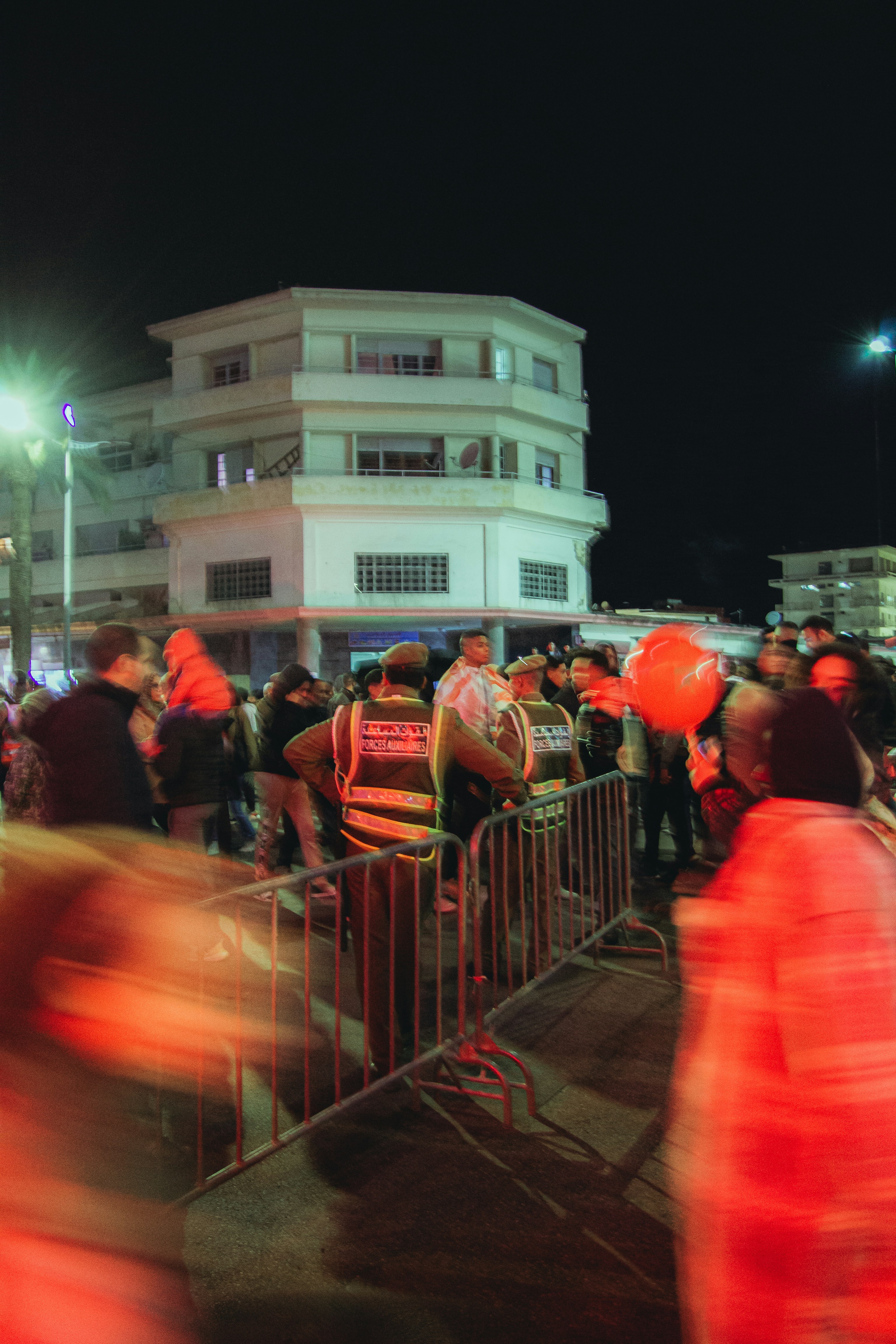 Night Street Rally: Neon Lights, Moving Crowd, and a Cornered Building