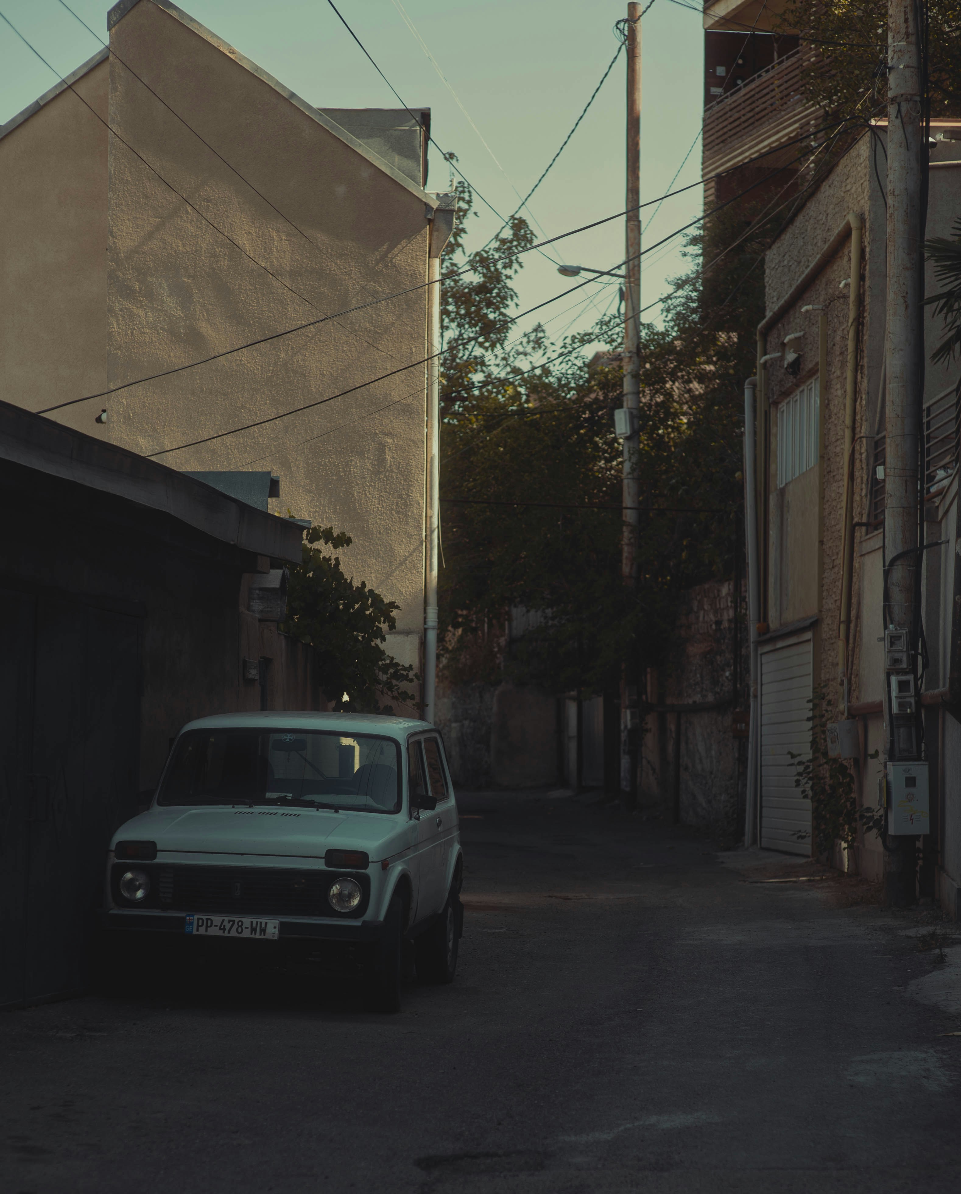 Narrow Street Quietly Framed by an Old Car and Drowsy Power Lines