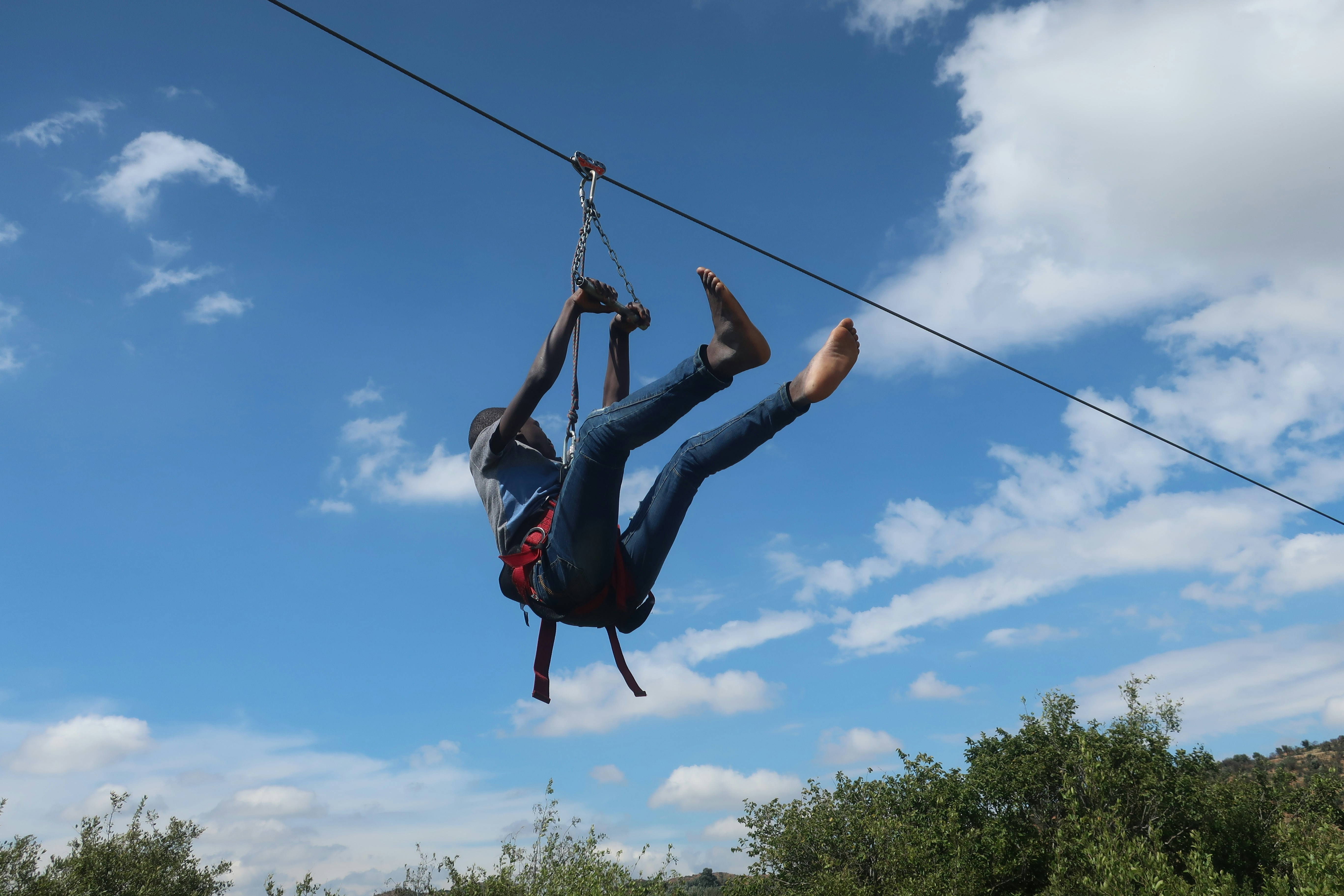 A Skyward Swing: Rider suspended mid-zip under a bright blue sky