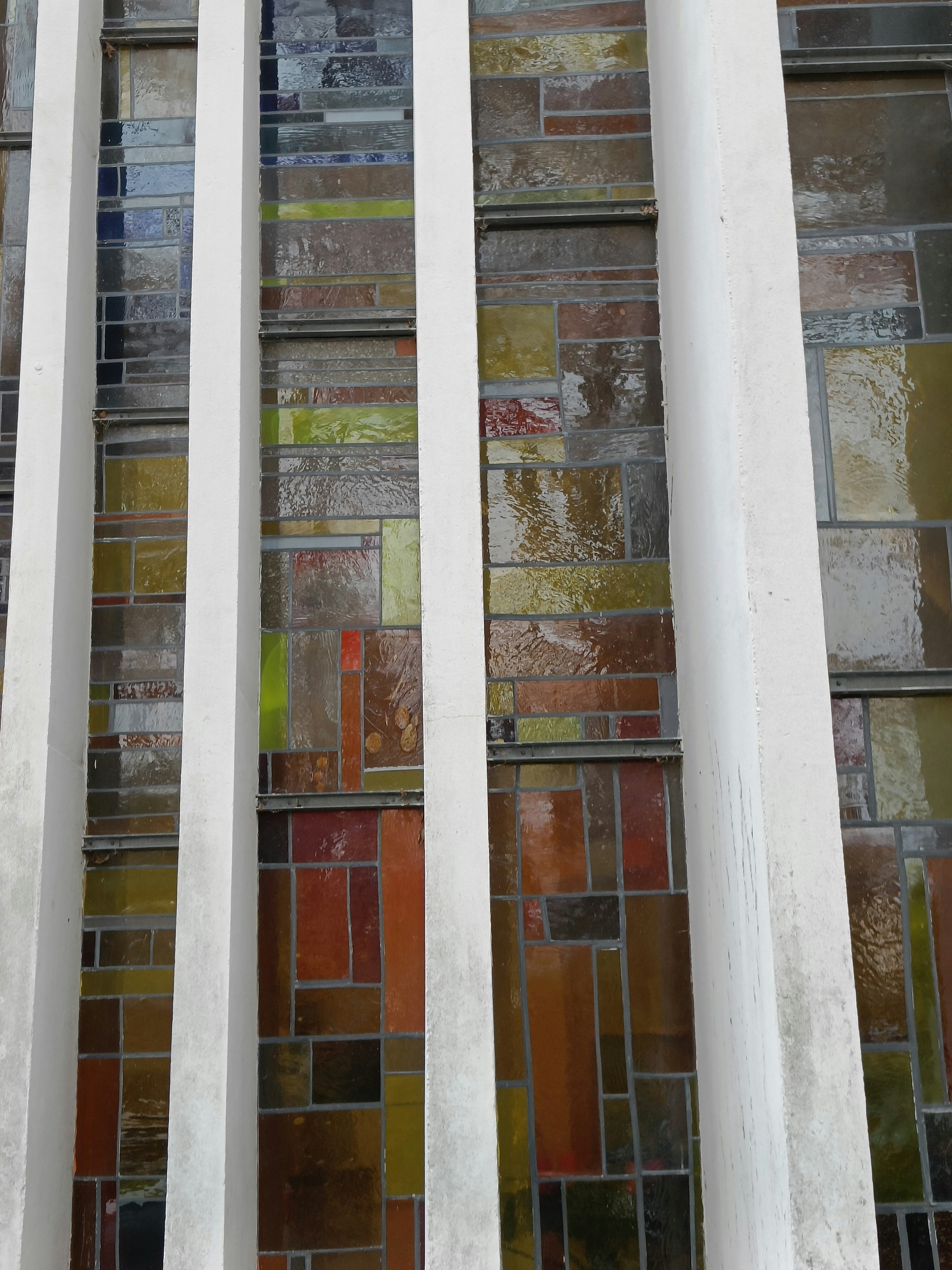 Colorful stained glass panels interspersed with white vertical bars, creating a striking contrast in an architectural setting.