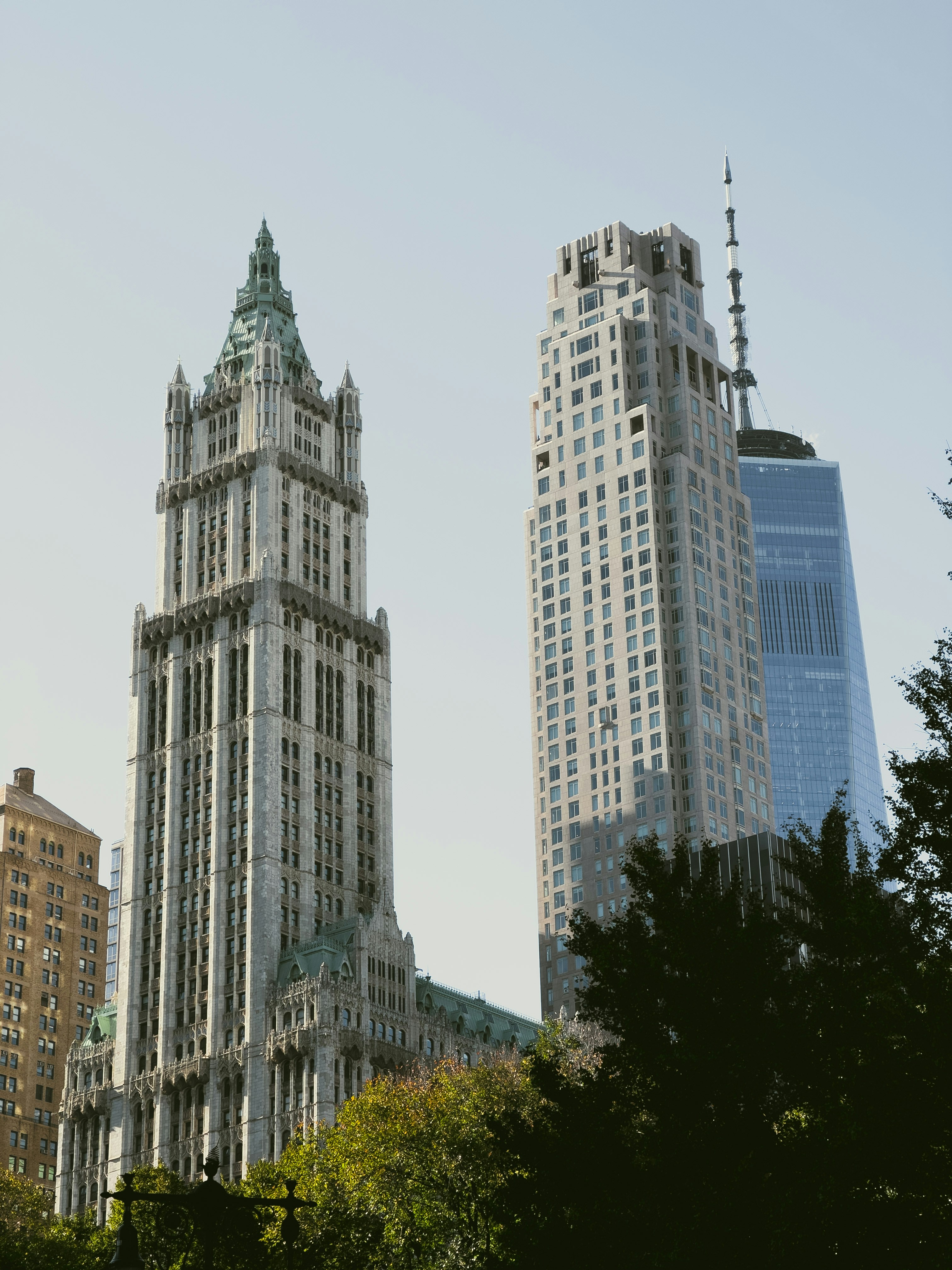 Gothic Tower Meets Glass Spire: A City Skyline Aligned Under Clear Sky