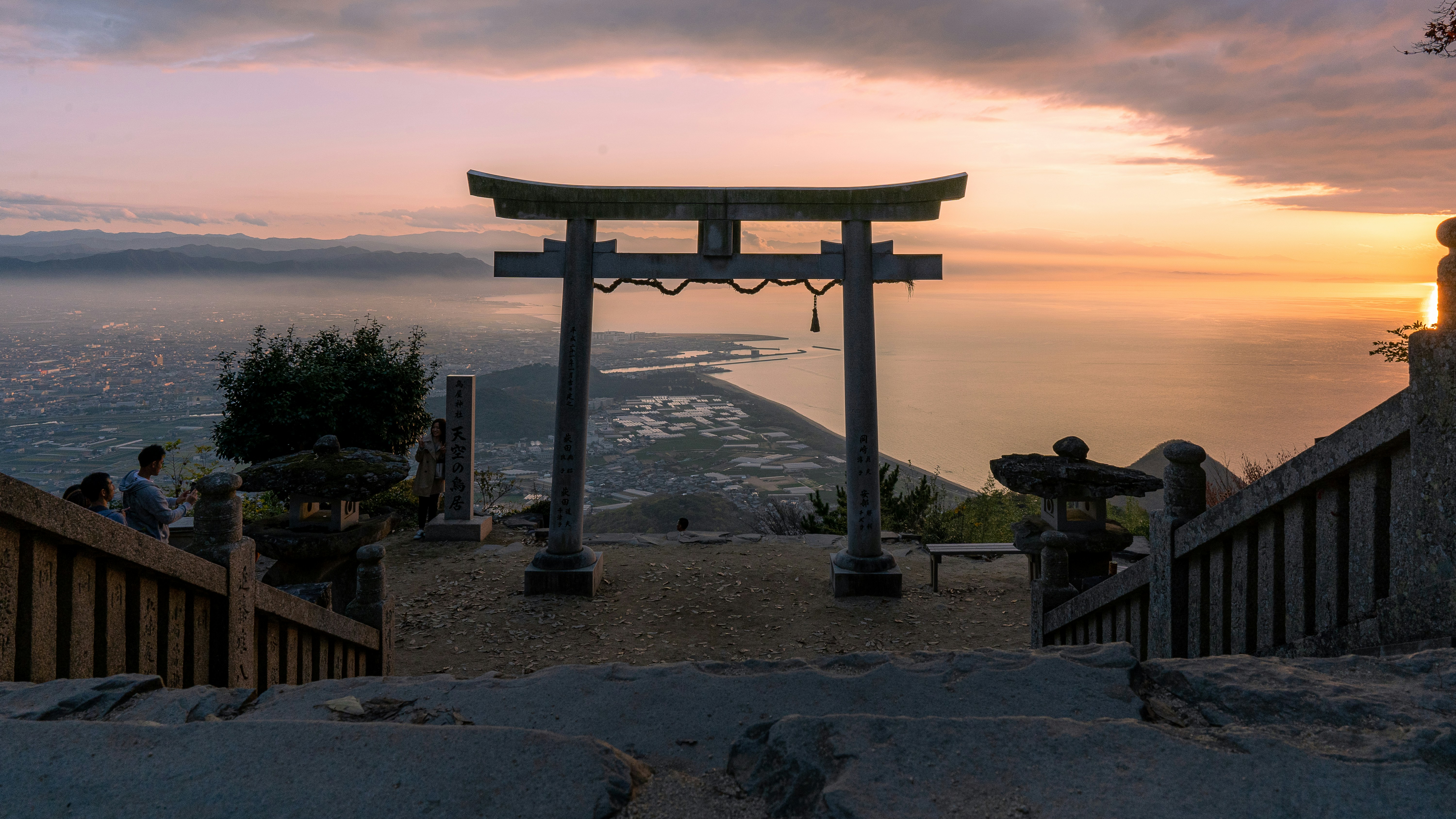 Sunset at Kan'onji Please credit me if you use my pictures, twitter Nefaarx or Instagram Raph_lop | a large arch with a railing and a body of water in the background
