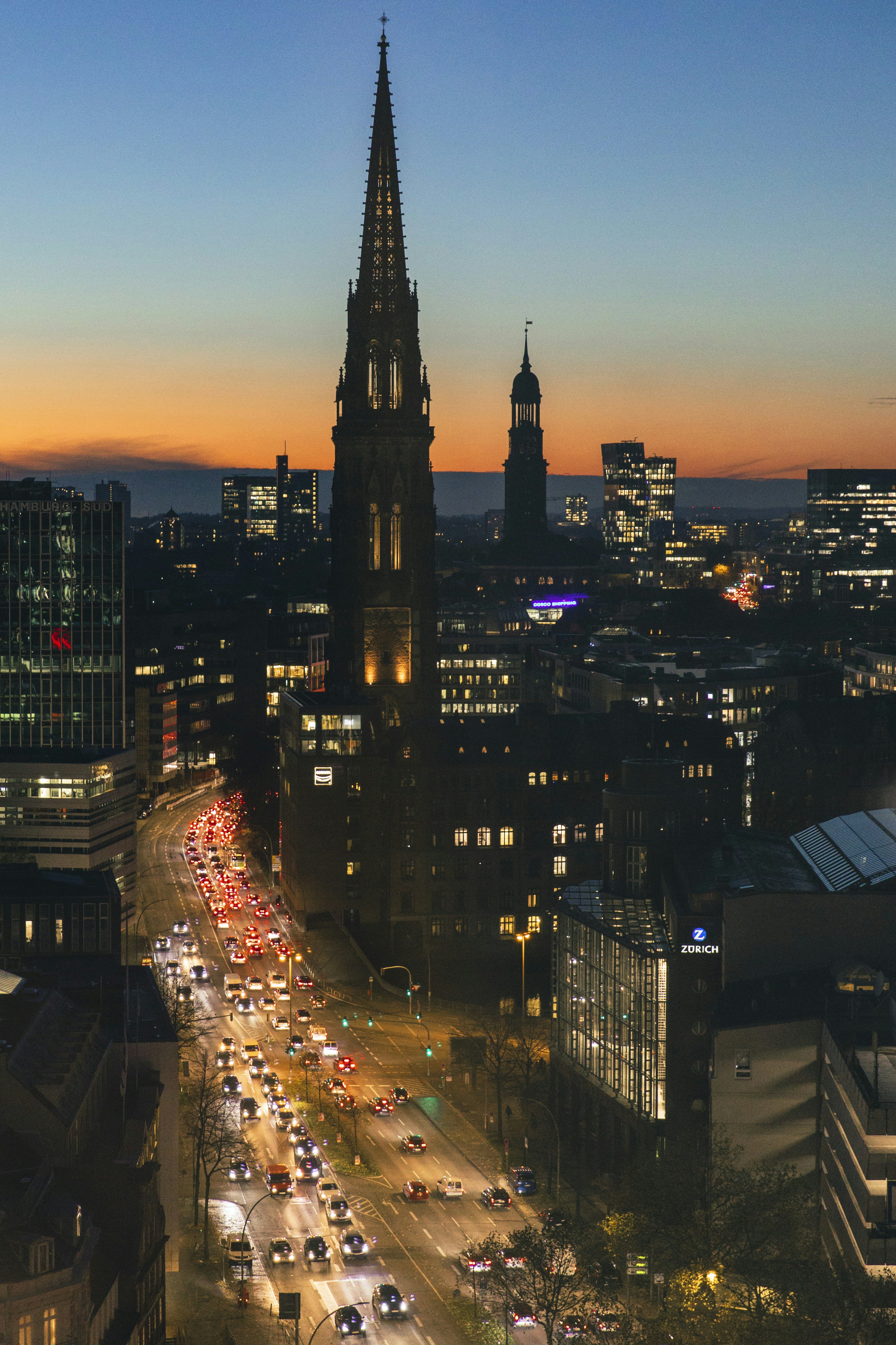 Zurich at Dusk: The Gothic Spire Crowned by Sunset Over a Car-Lit City