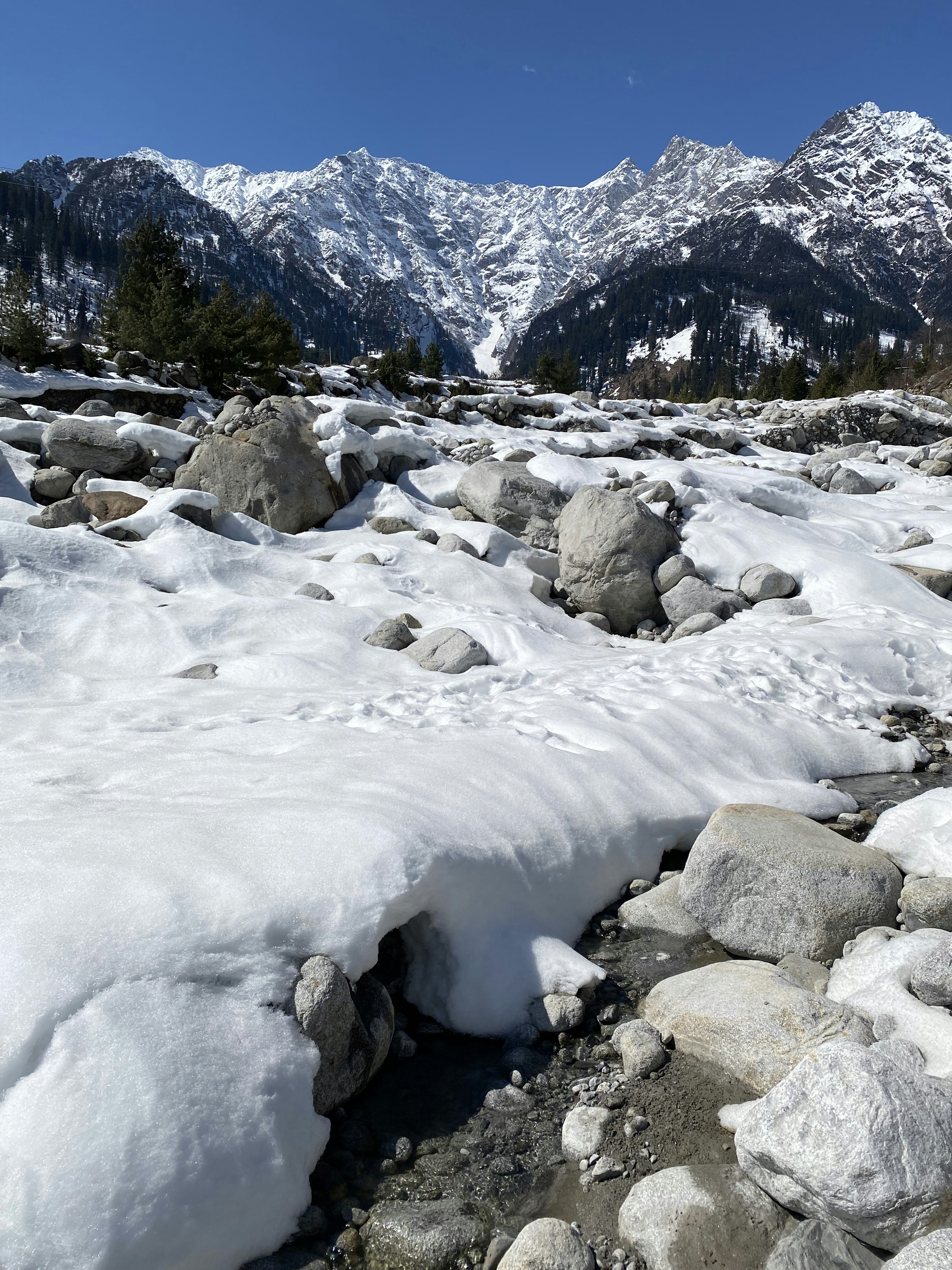 A rocky area with snow and mountains in the background photo – Free ...
