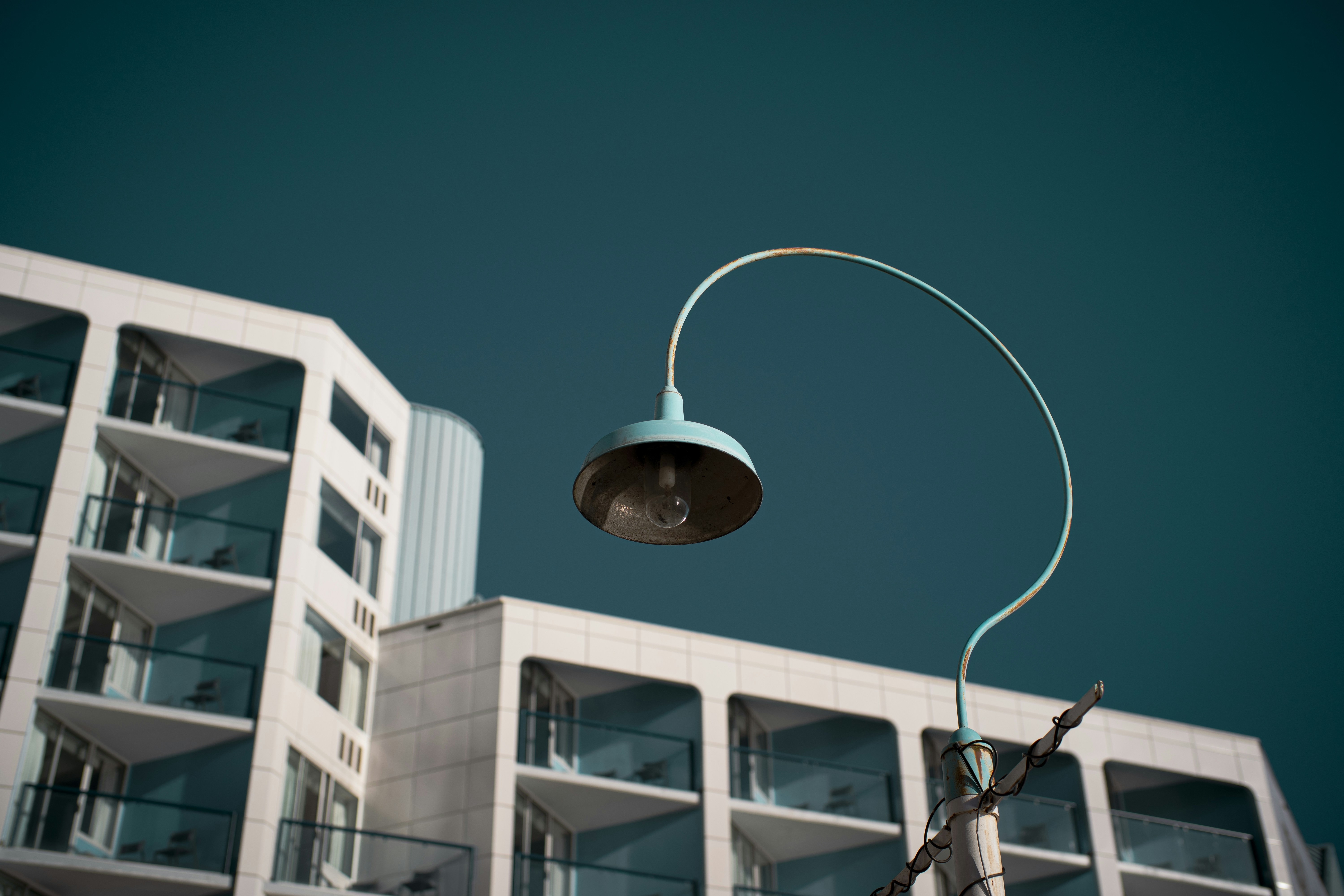 Curved Lamp Arch Framing a Teal Urban Facade