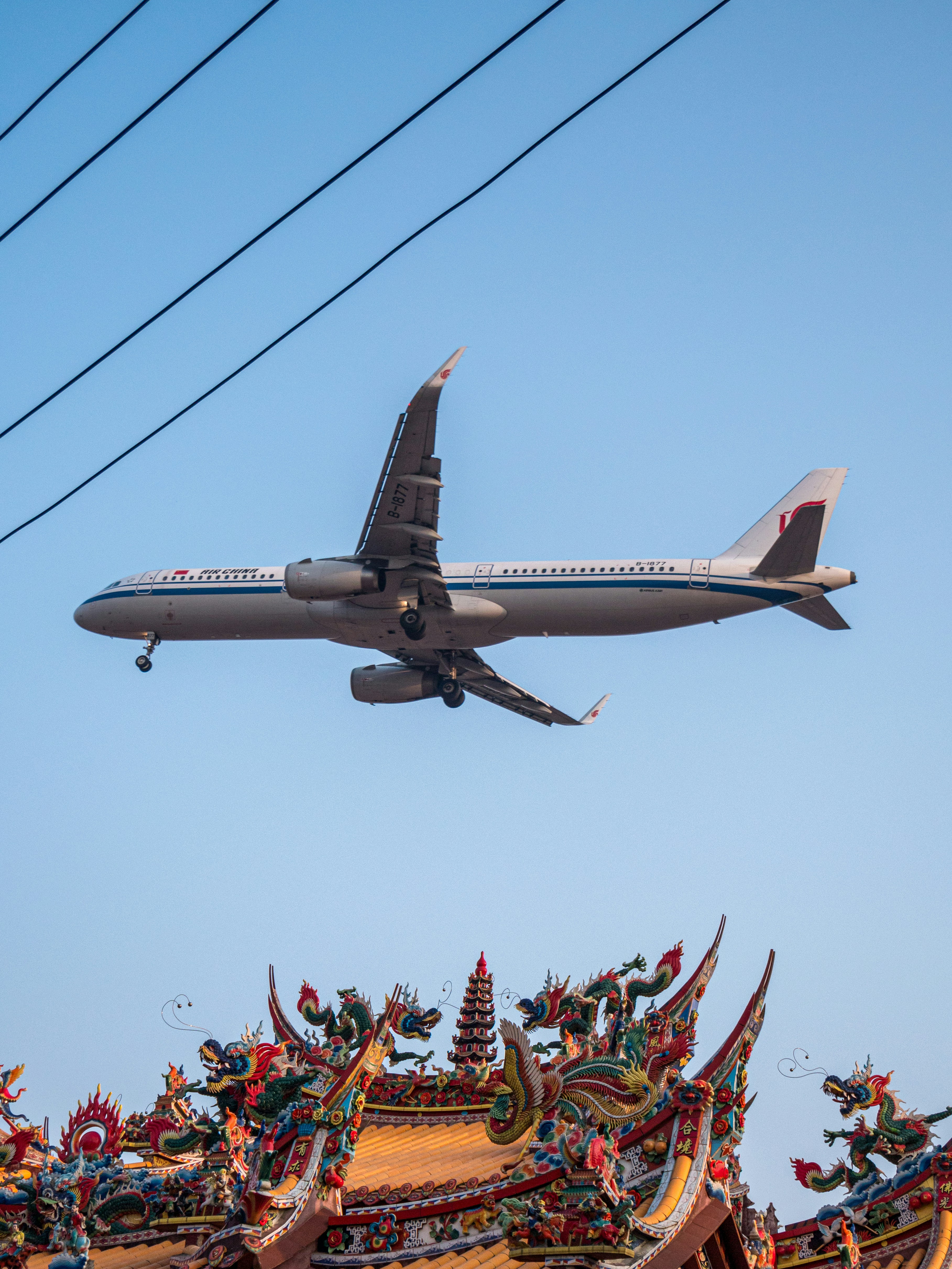 Skybound Crossing: Airliner Over Ornate Roofs