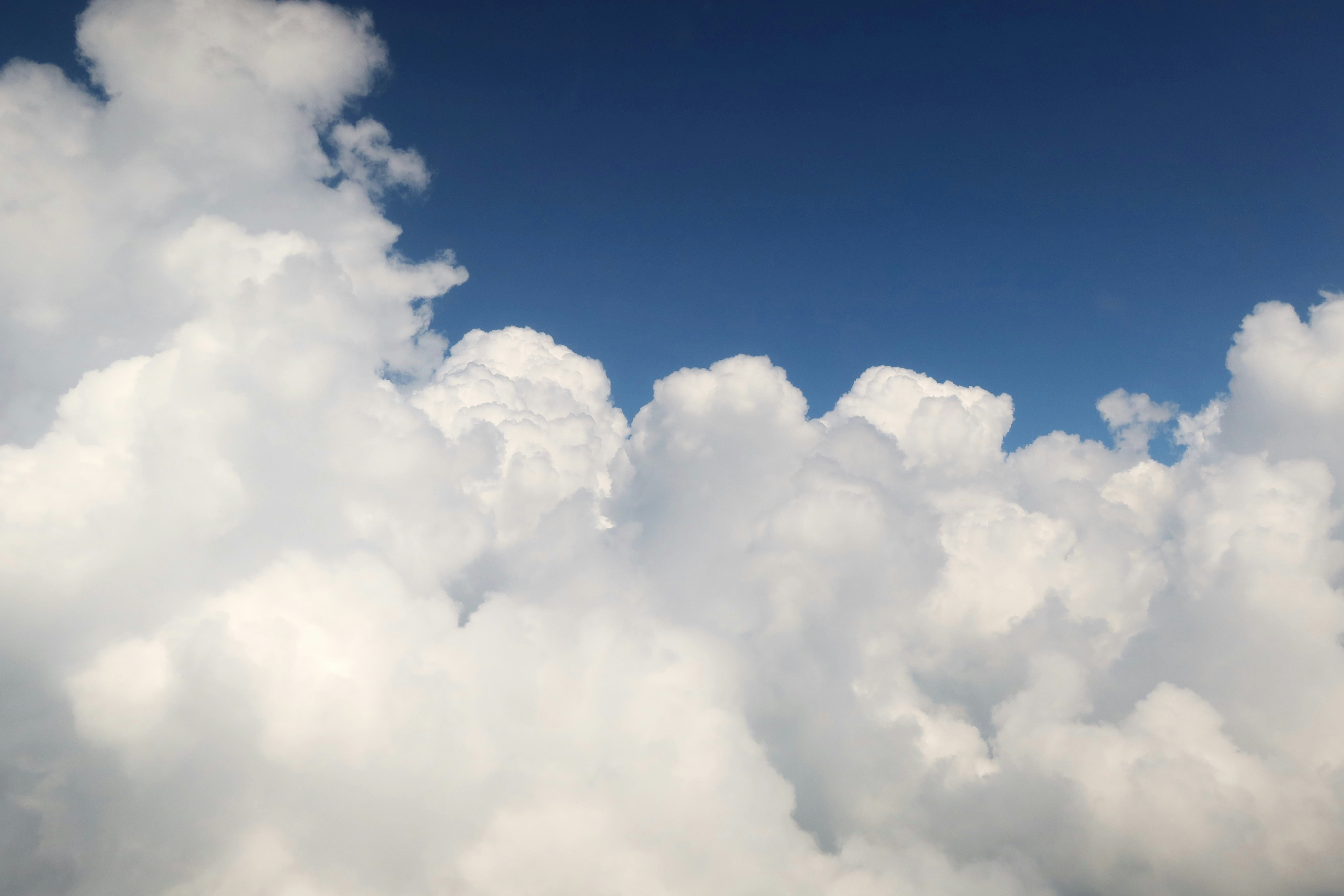 Fluffy white clouds billowing against a deep blue sky, creating a serene atmosphere. This image captures the essence of a tranquil sky scene.