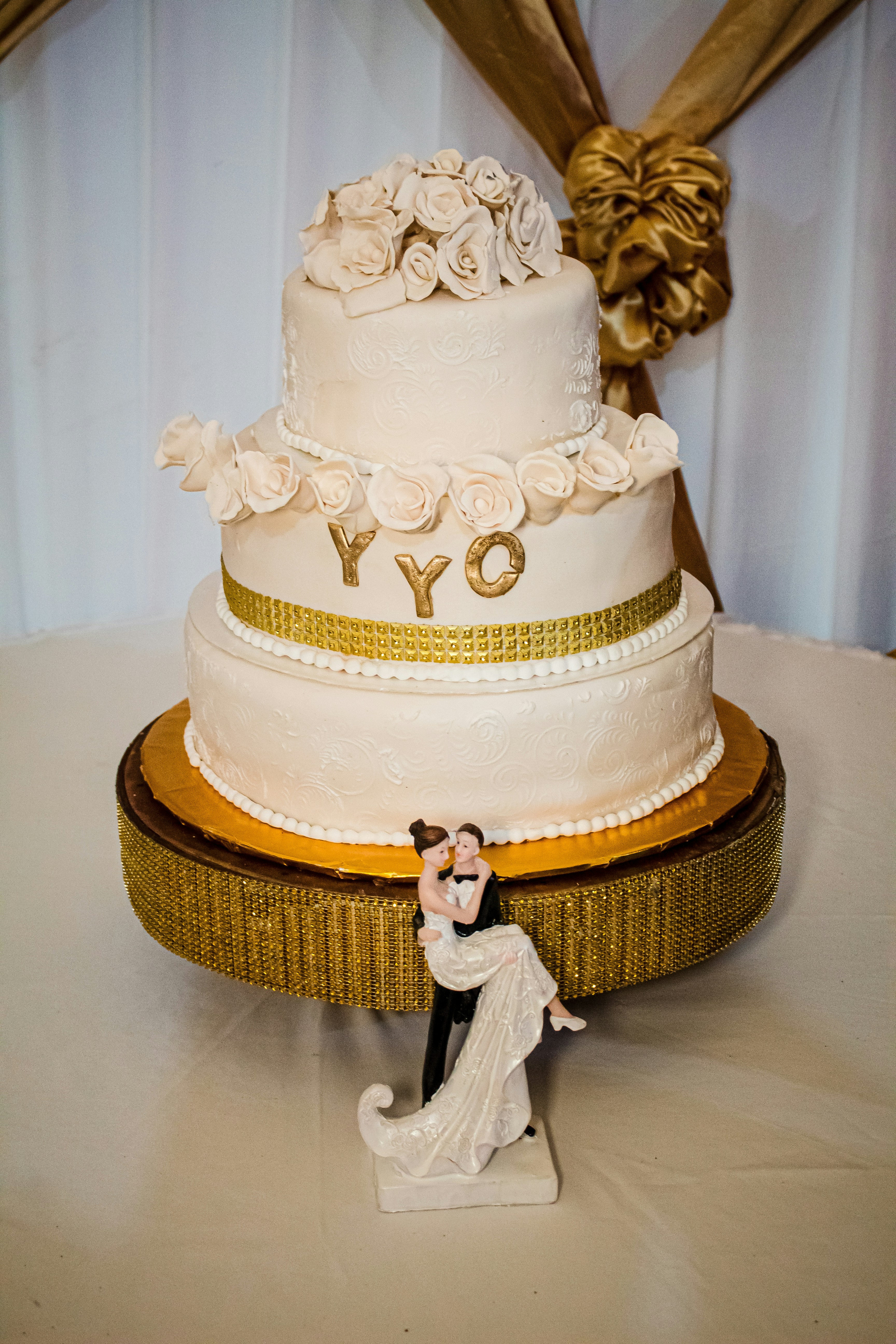 Three-Tier Ivory Wedding Cake with Cream Roses and a Gold Bead Ribbon