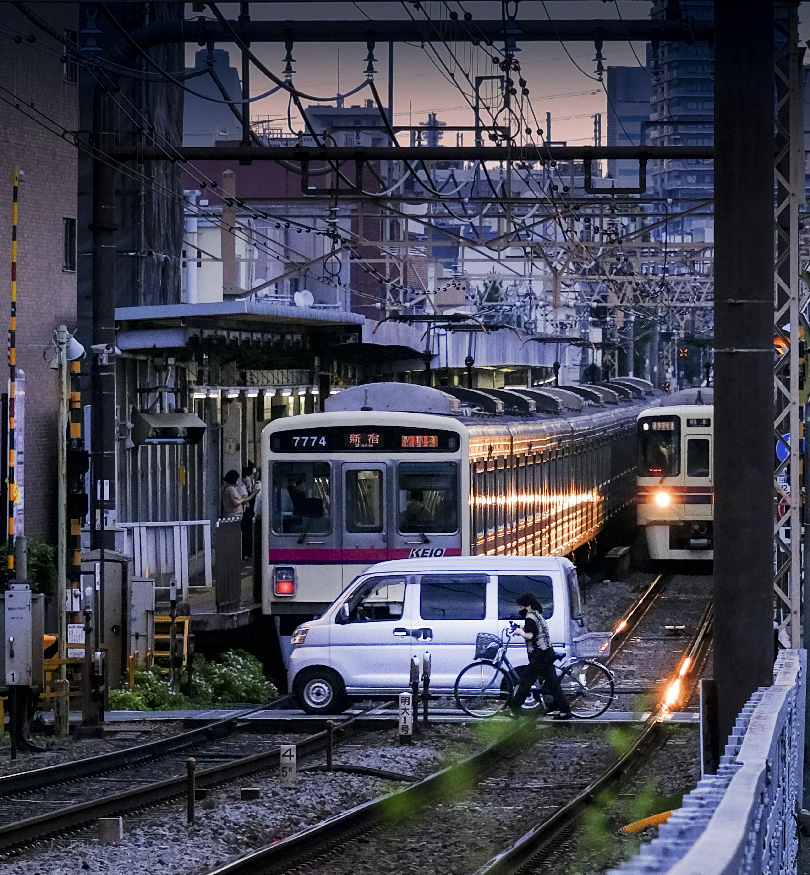 Dusk Rail Yard: Vans, Bicycles and Trains Beneath a Web of Wires