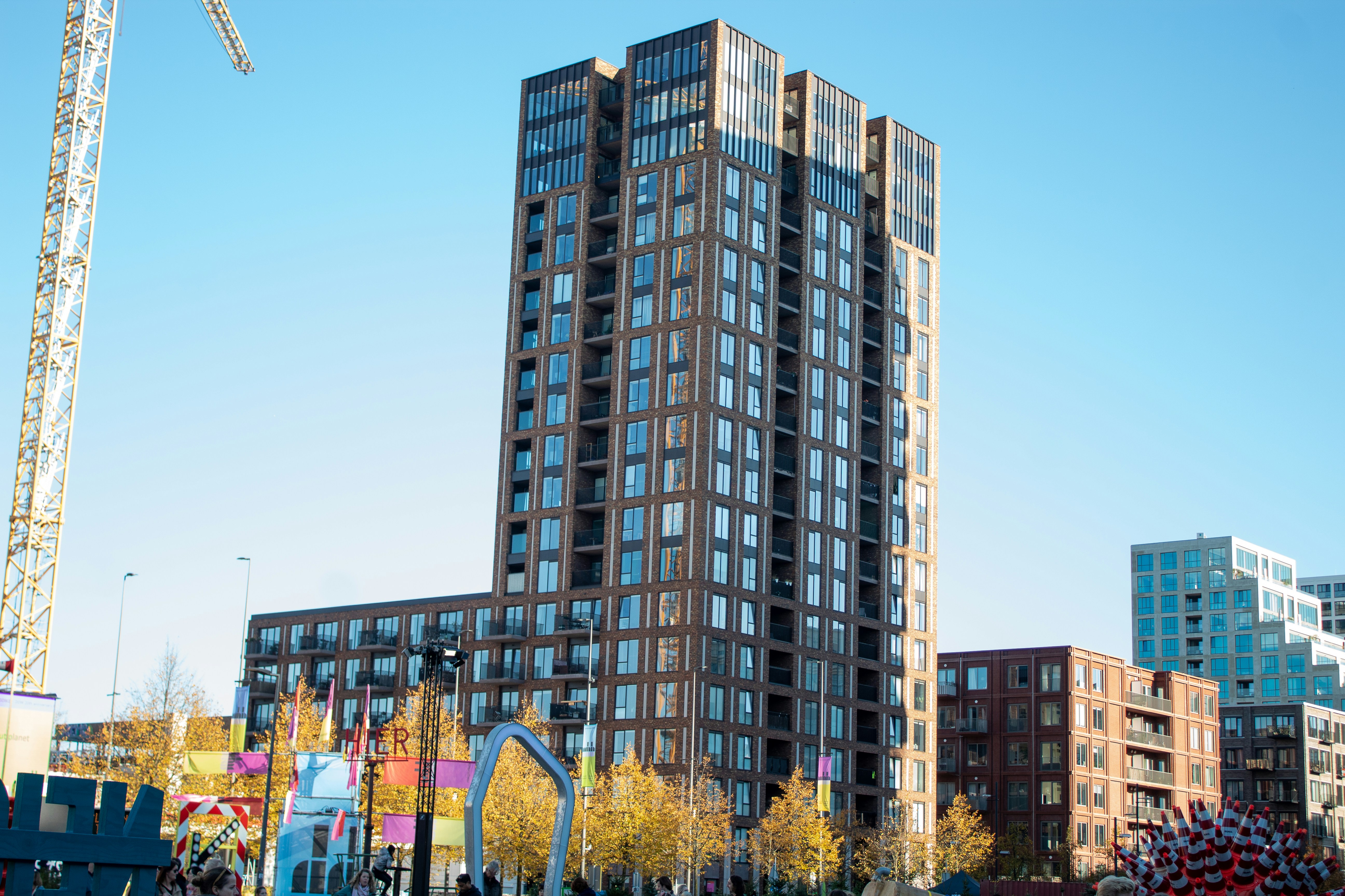 Modern high-rise building against a clear blue sky with a construction crane nearby.