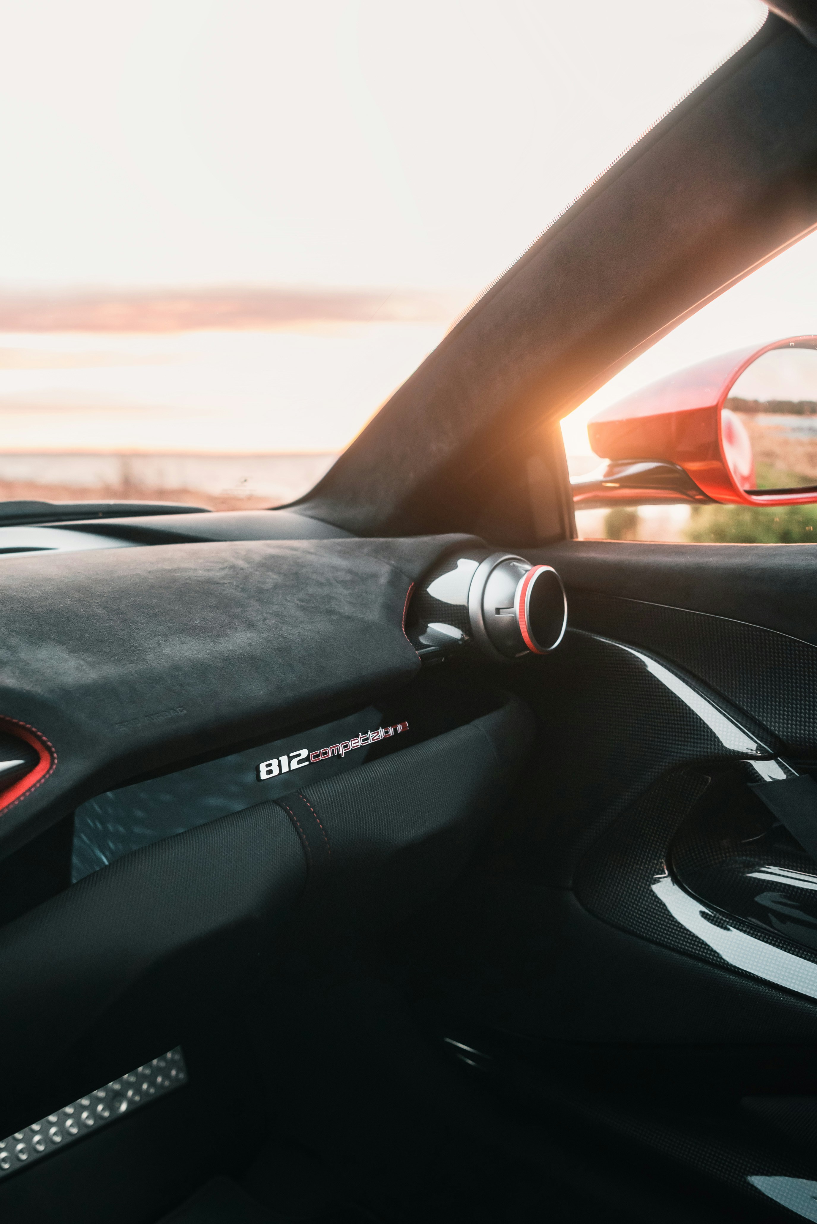 Sunlit Carbon and Red Accents: Inside a Ferrari 812 Competizione Cabin at Sunset