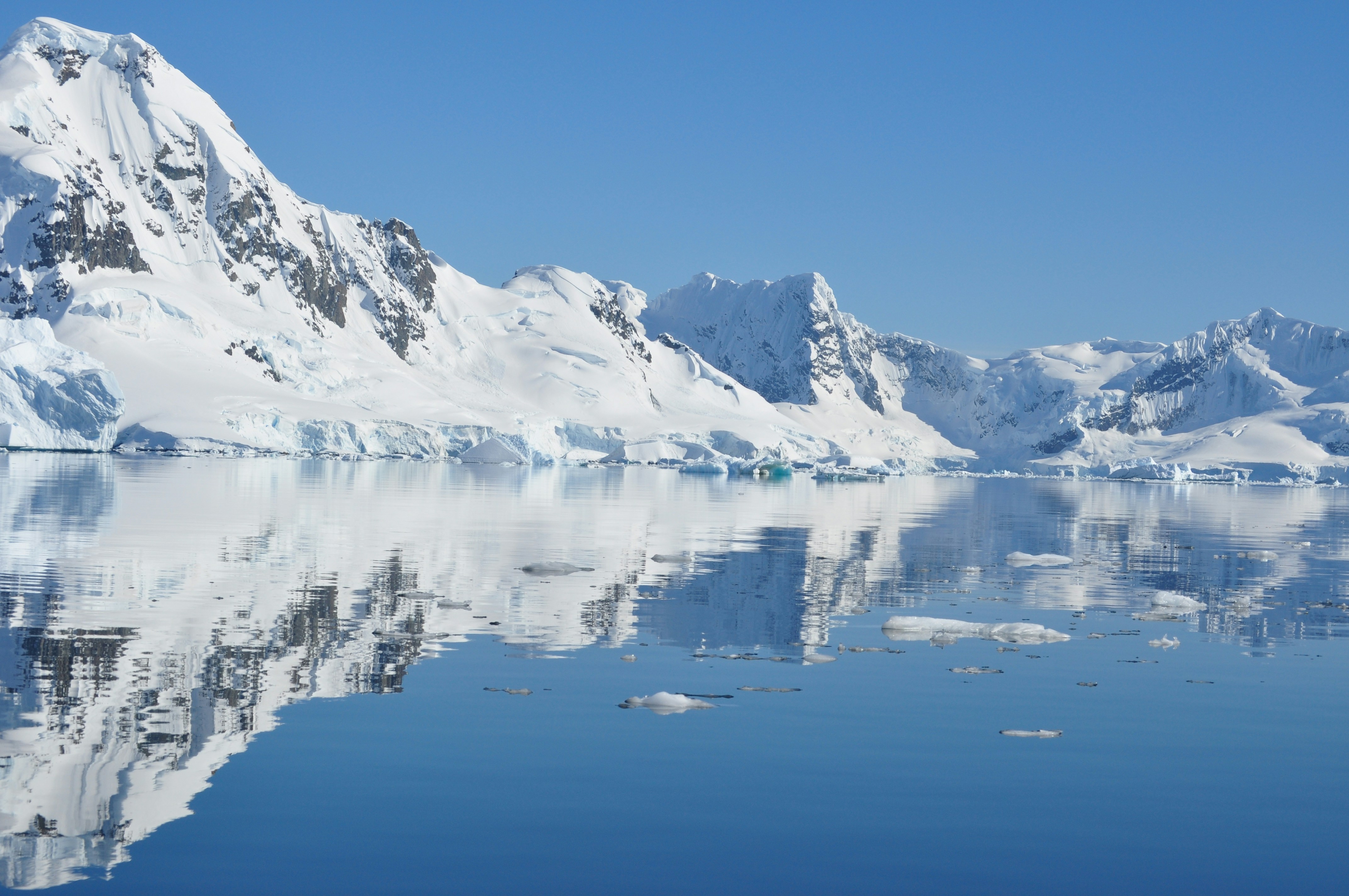 A body of water with snowy mountains in the background photo – Free ...