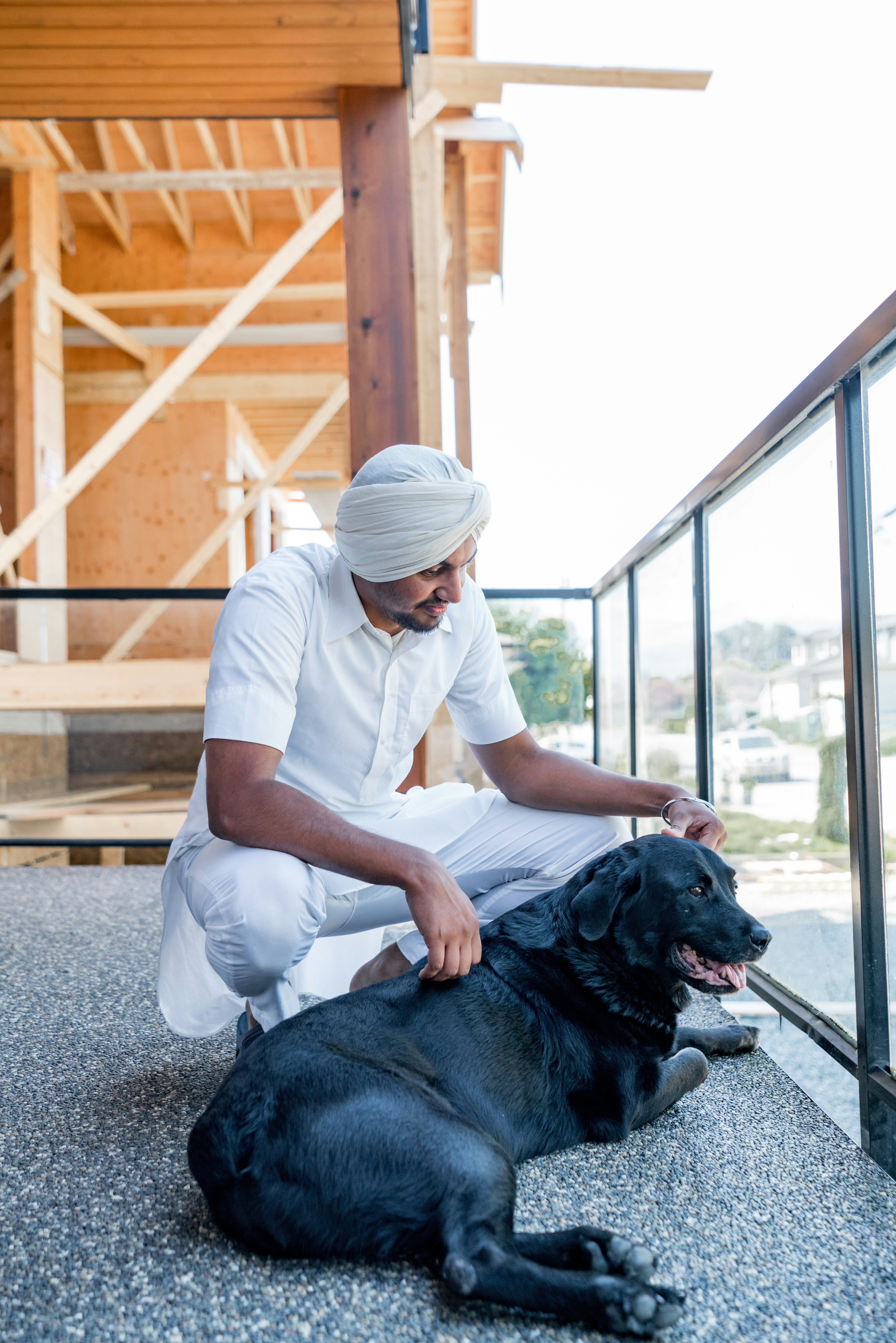 Turbaned calm: a man and his black lab share a quiet balcony moment