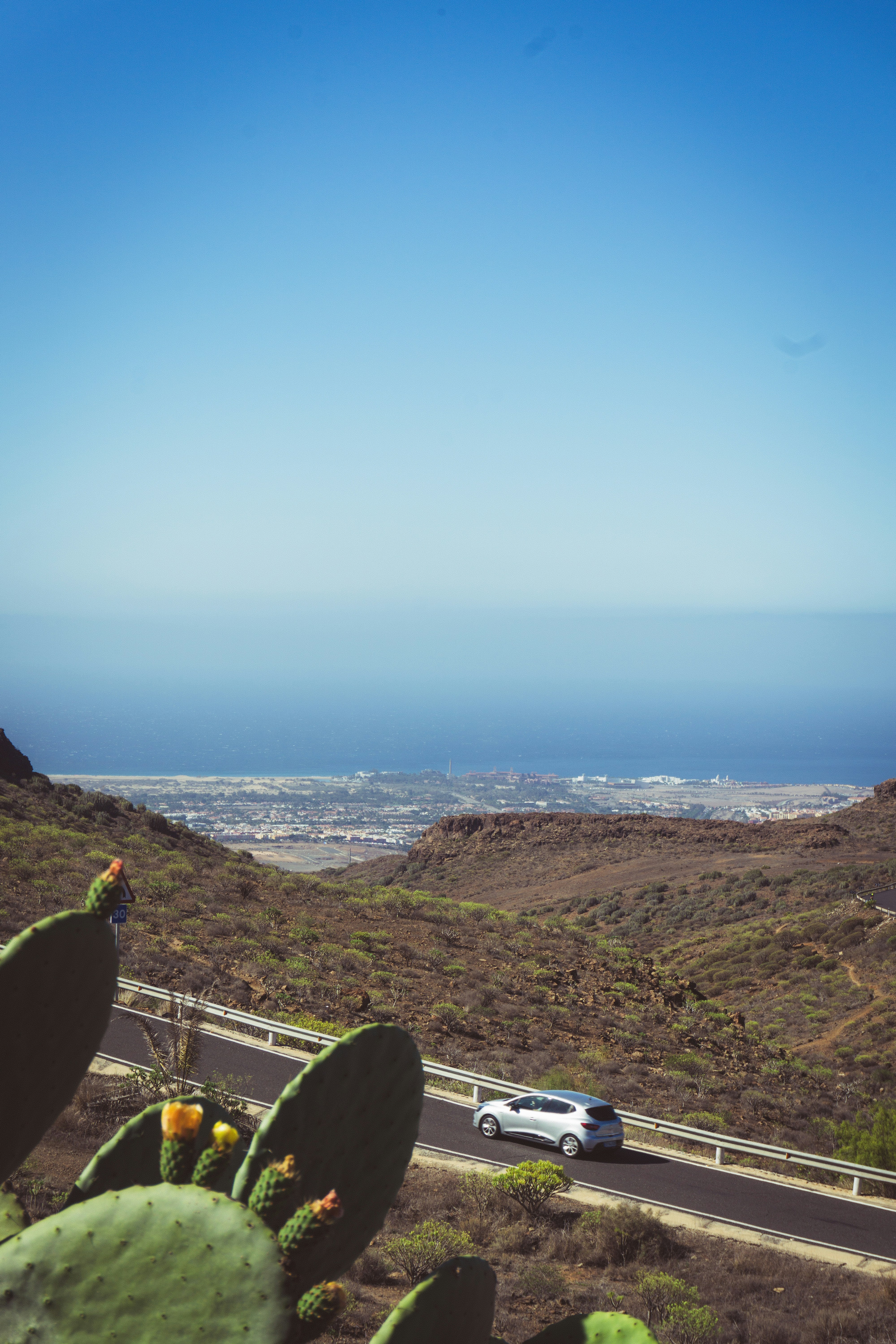 a car driving on a road near a beach and ocean