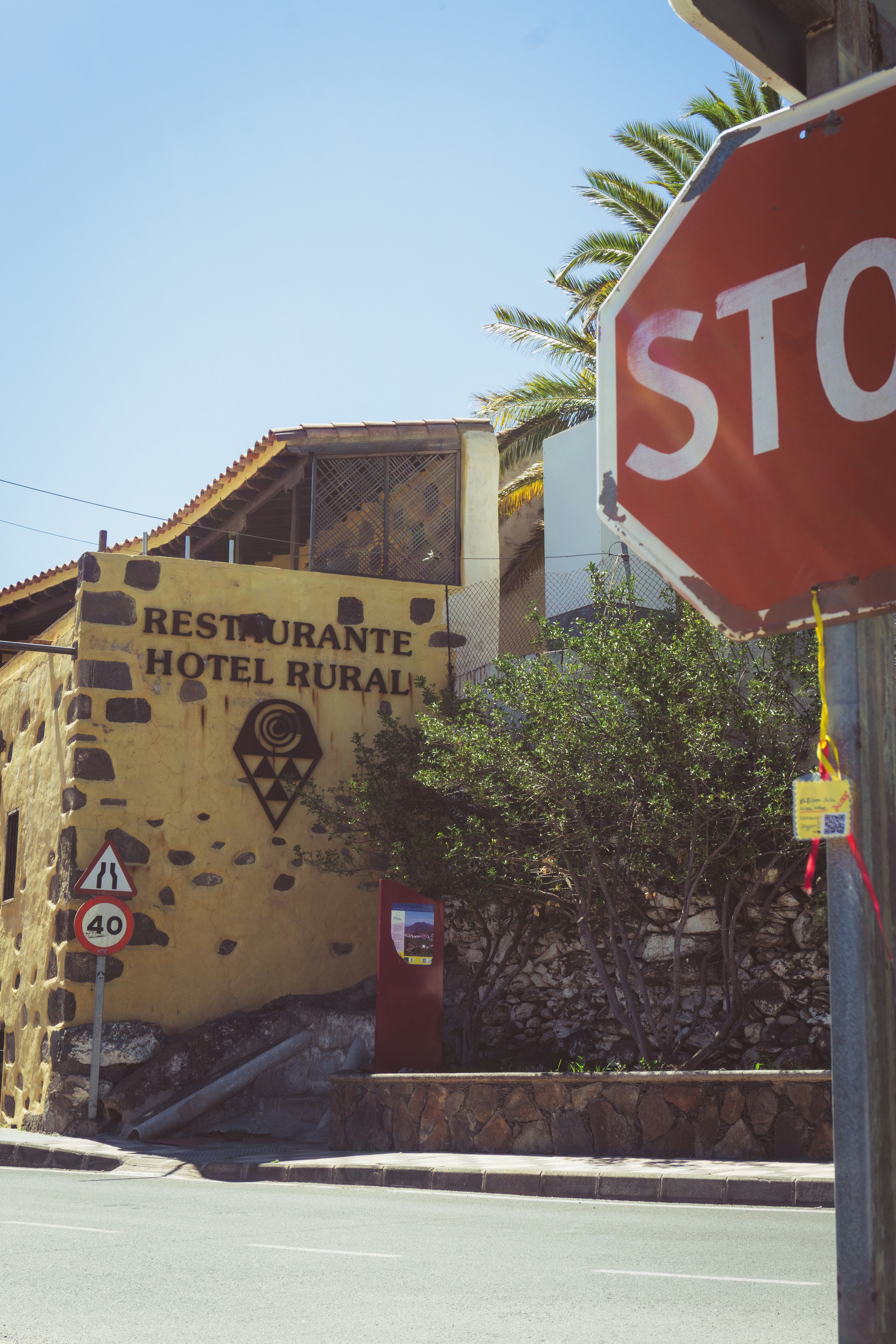 Rural Rest: A Weathered Hotel Sign Beneath a Stop Sign and Palm Shade