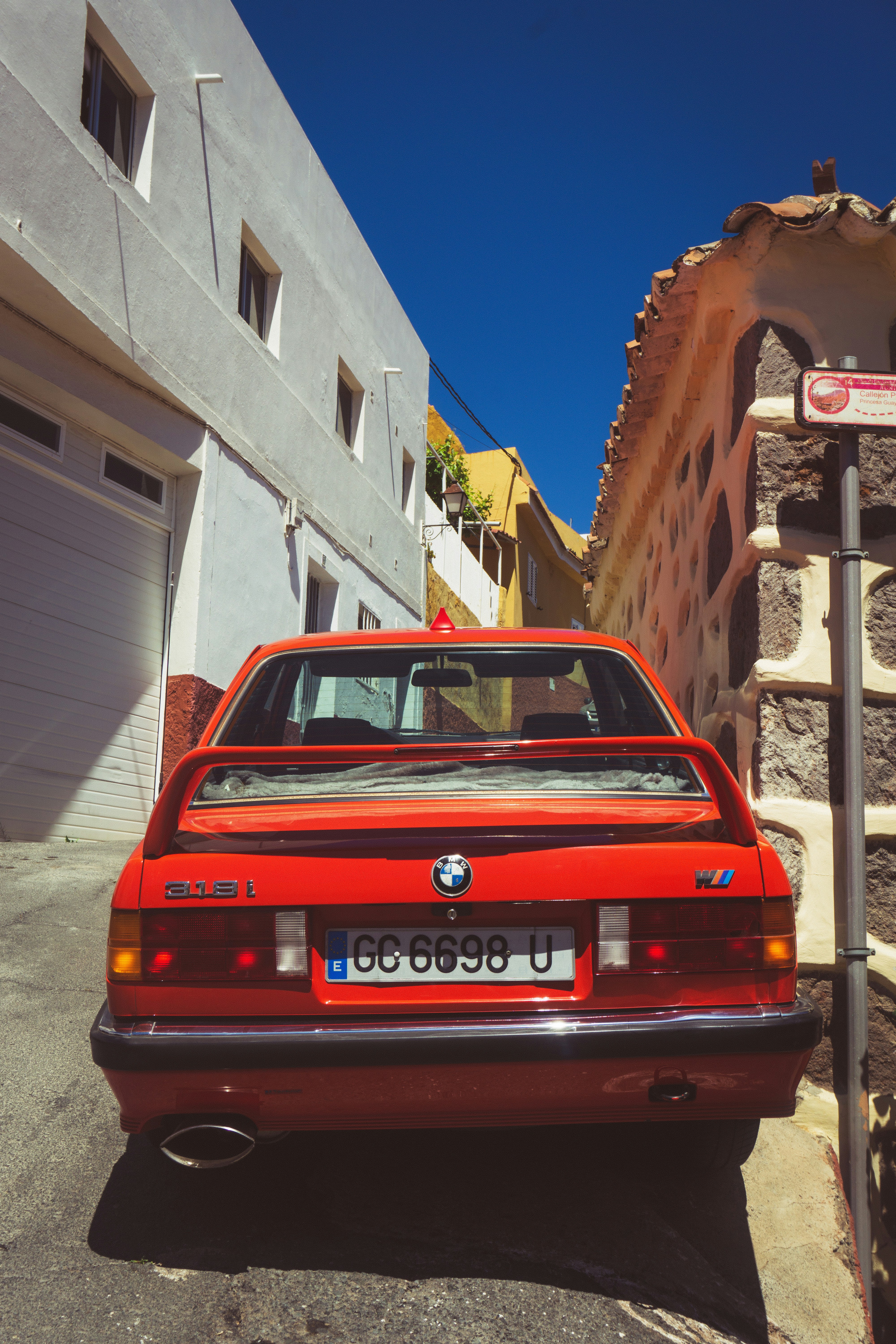 Rear-View Red: A Sunlit European Street with a Classic BMW