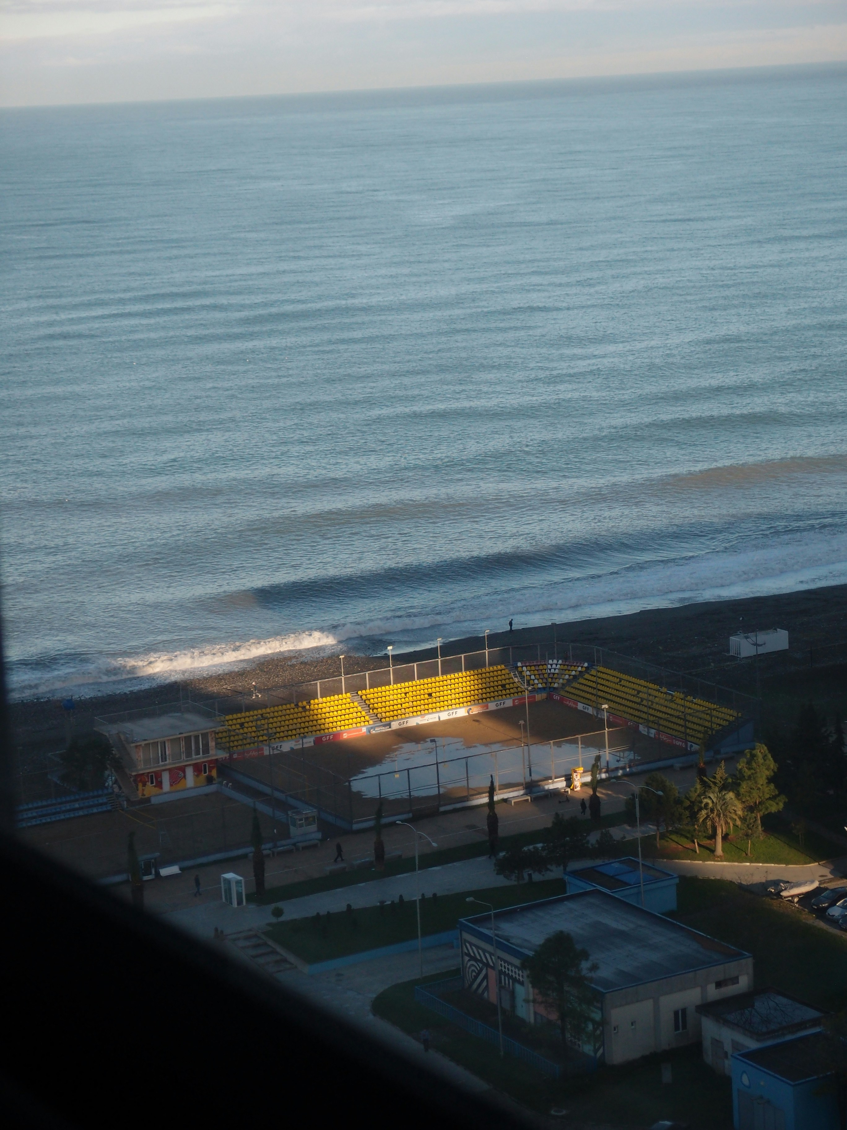 Rimmed by Sea: A Balcony View Over a Fenced Arena