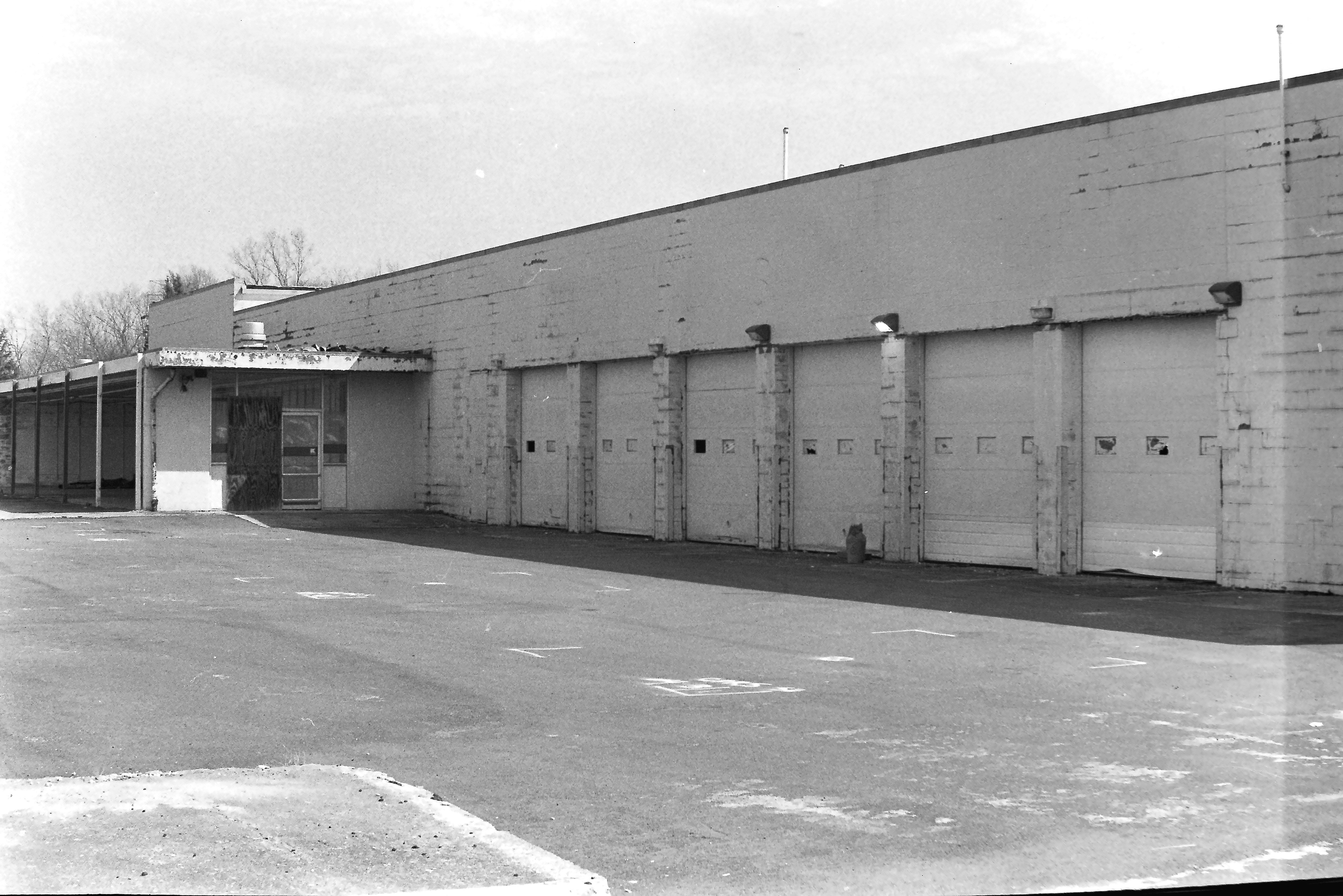 Row of closed garage doors on an industrial warehouse under an overcast sky.