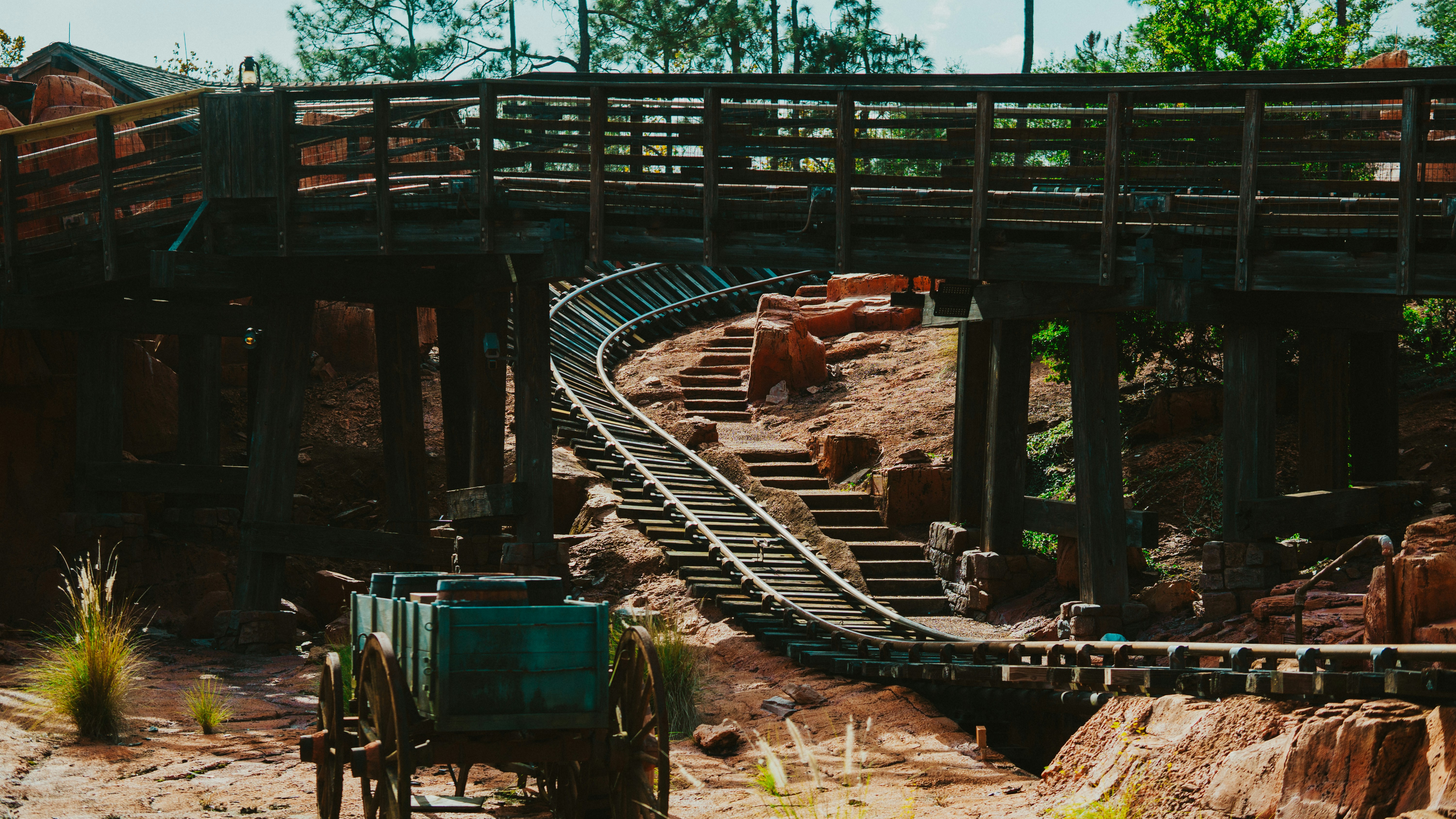 Blue Cart on a Timber-Coaster Arc Beneath a Weathered Bridge