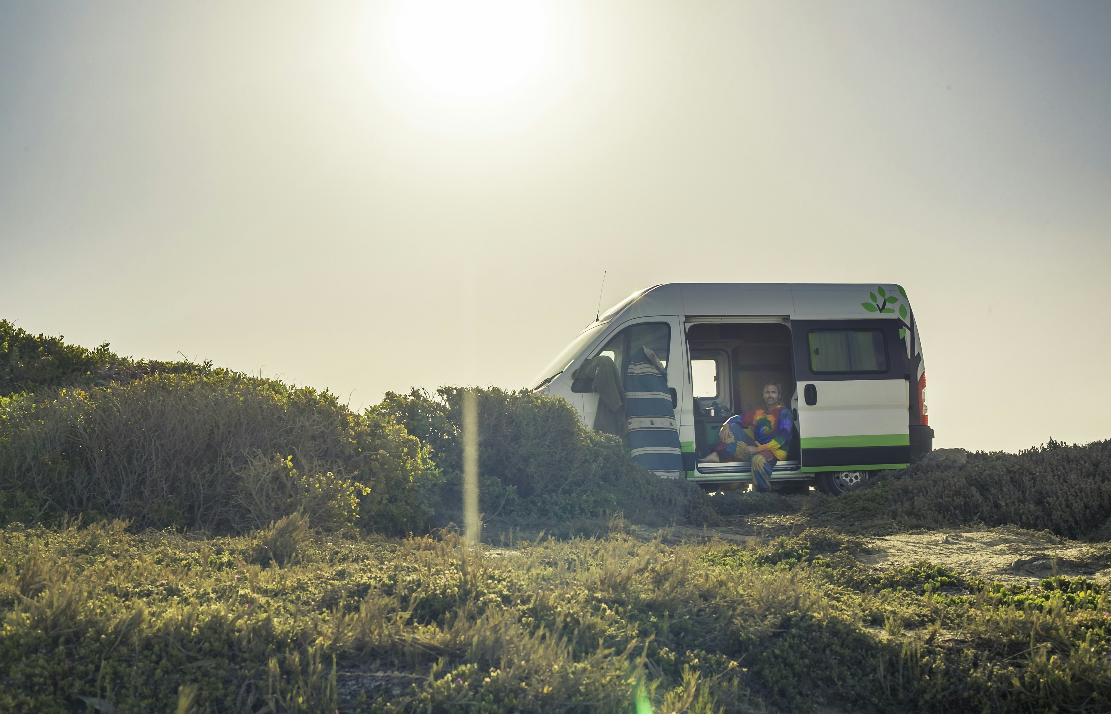 Duneside Pause: A Sunlit Camper Van Resting by Coastal Scrub