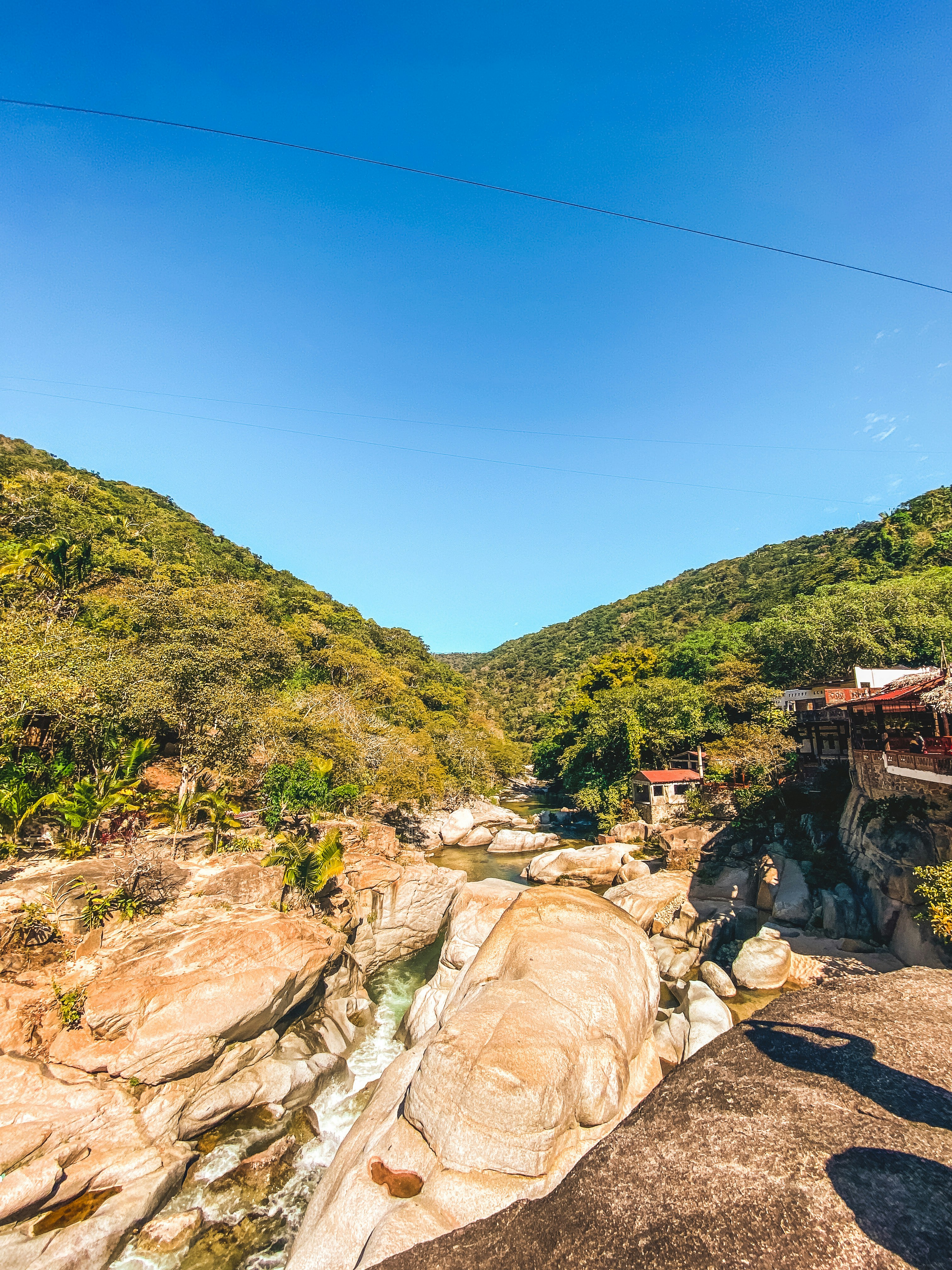 Sunlit Gorge: River Between Warm Granite and Village Cliffs
