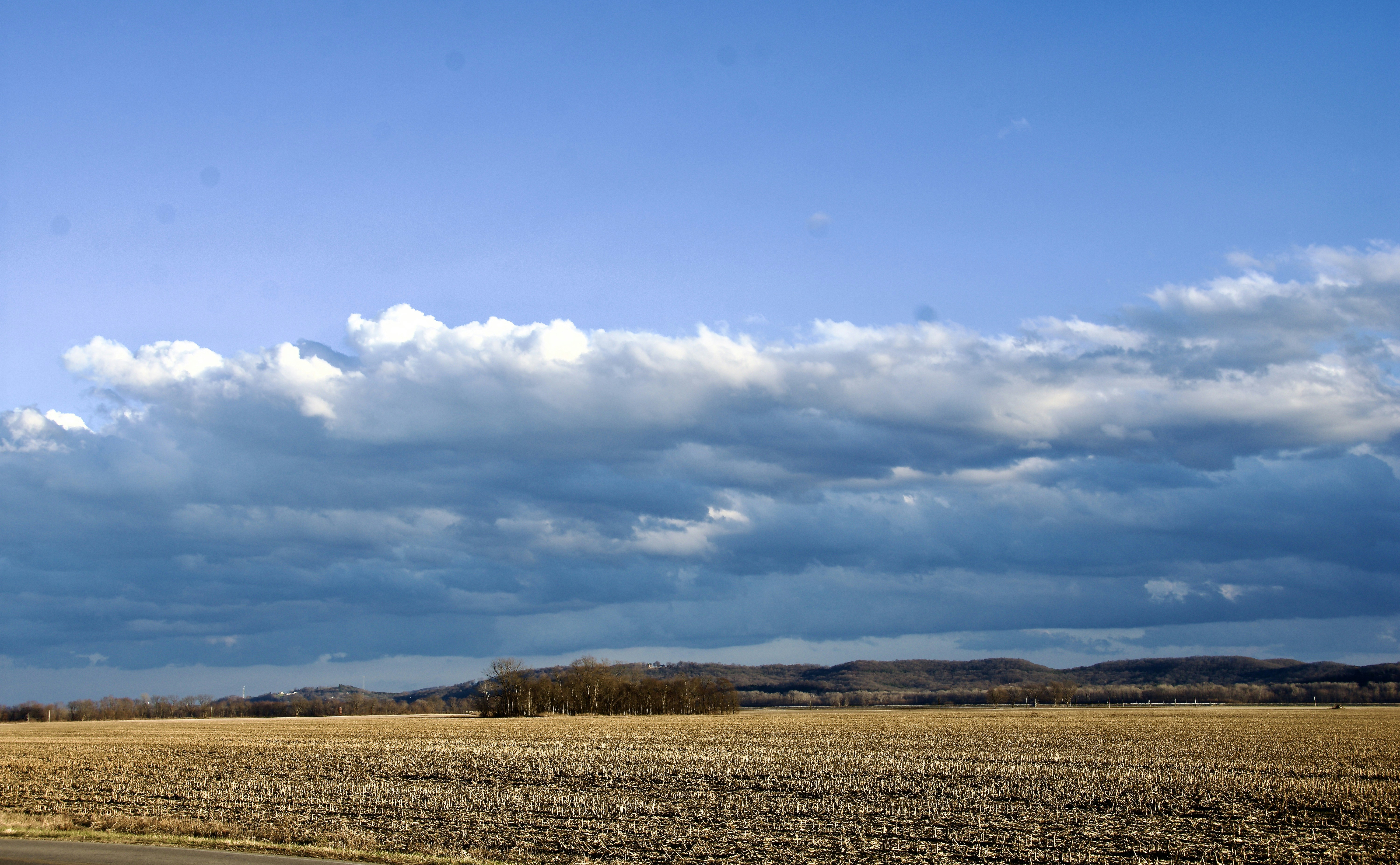 Foto zum Thema Ein großes offenes Feld mit Wolken am Himmel ...