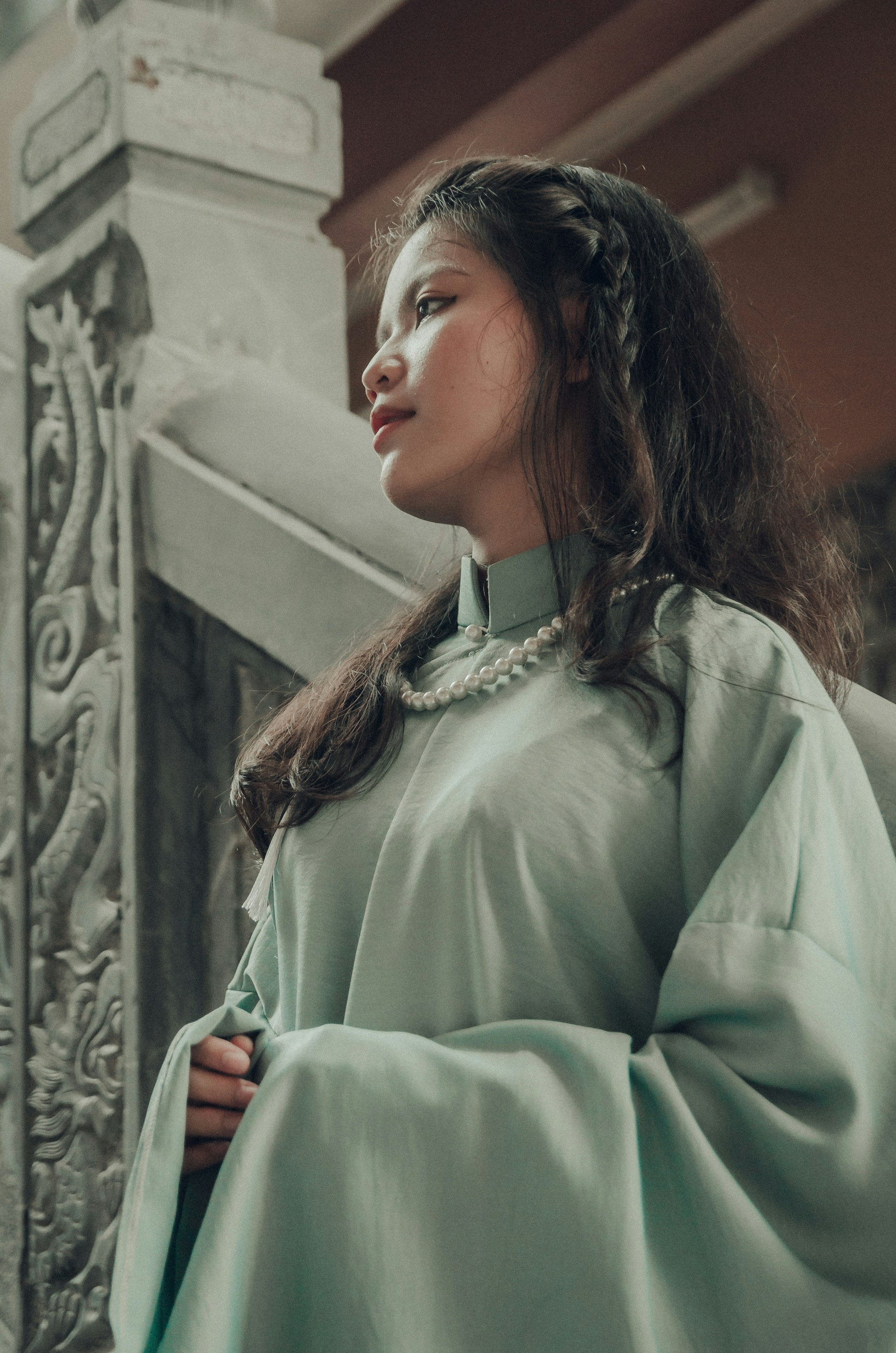 Beside the carved pillar: a poised portrait in soft mint robes