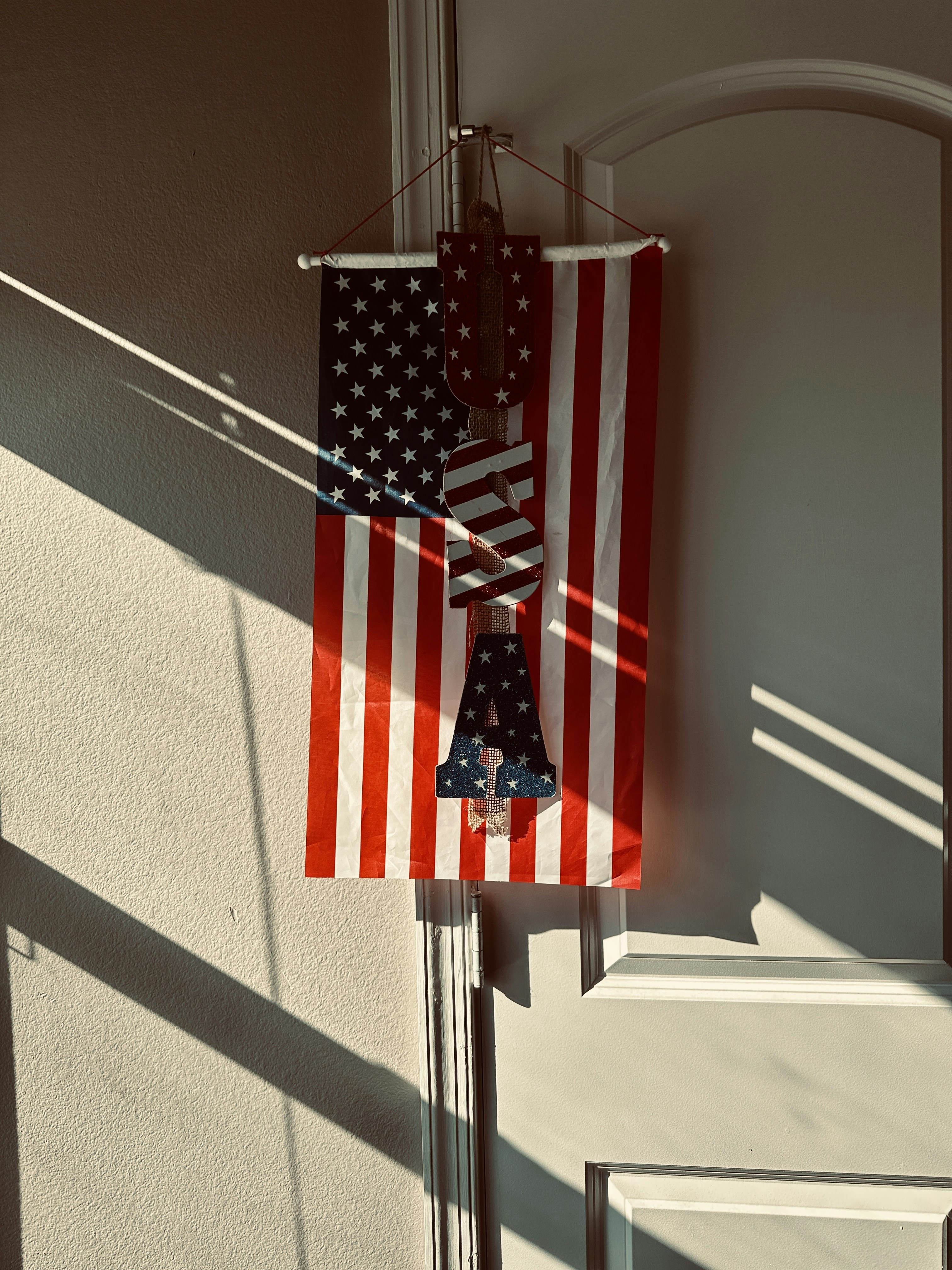 Sunlit Stars and Stripes Draped Over a Quiet Doorway
