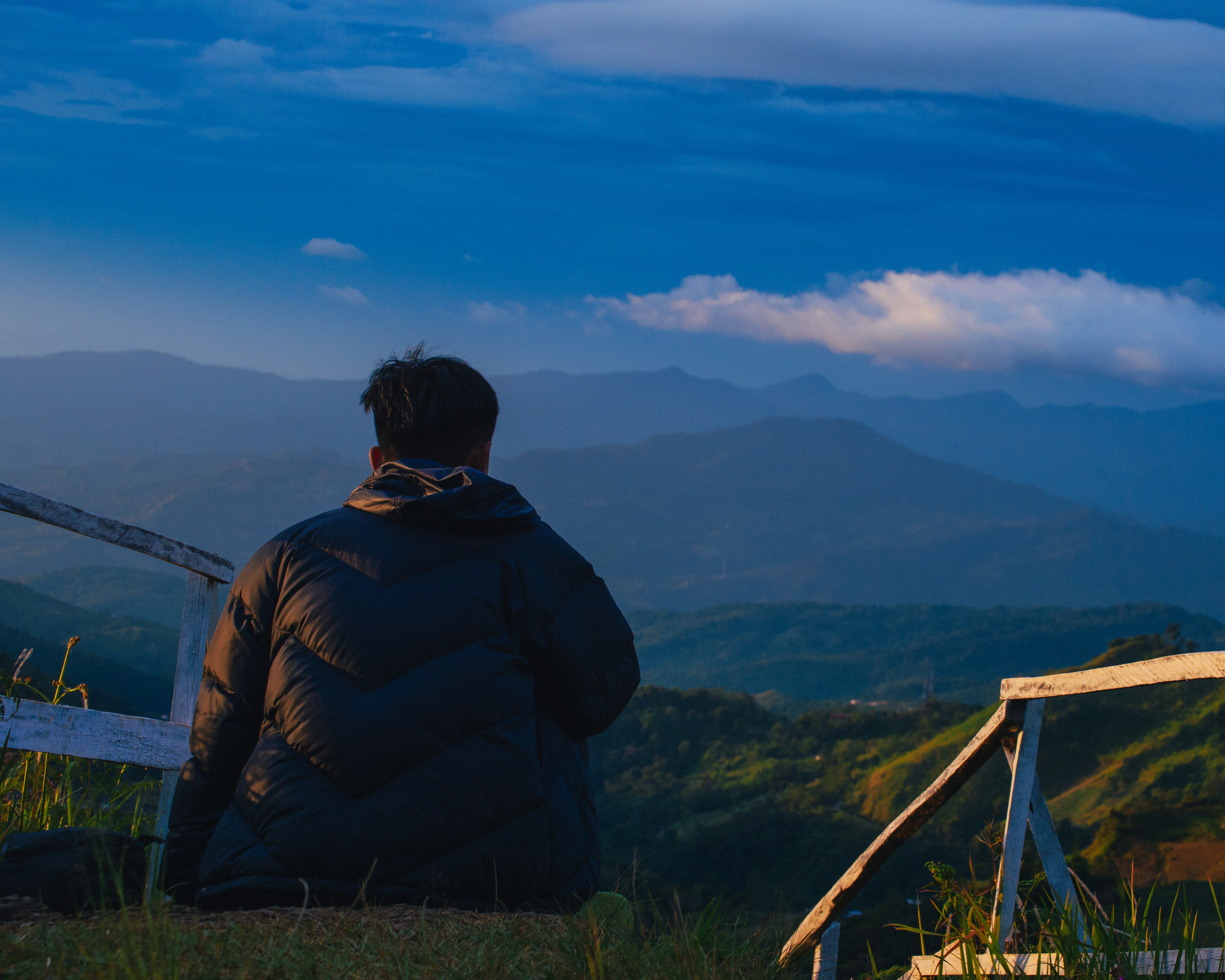 Foto Una persona sentada en una colina mirando un valle – Imagen ...