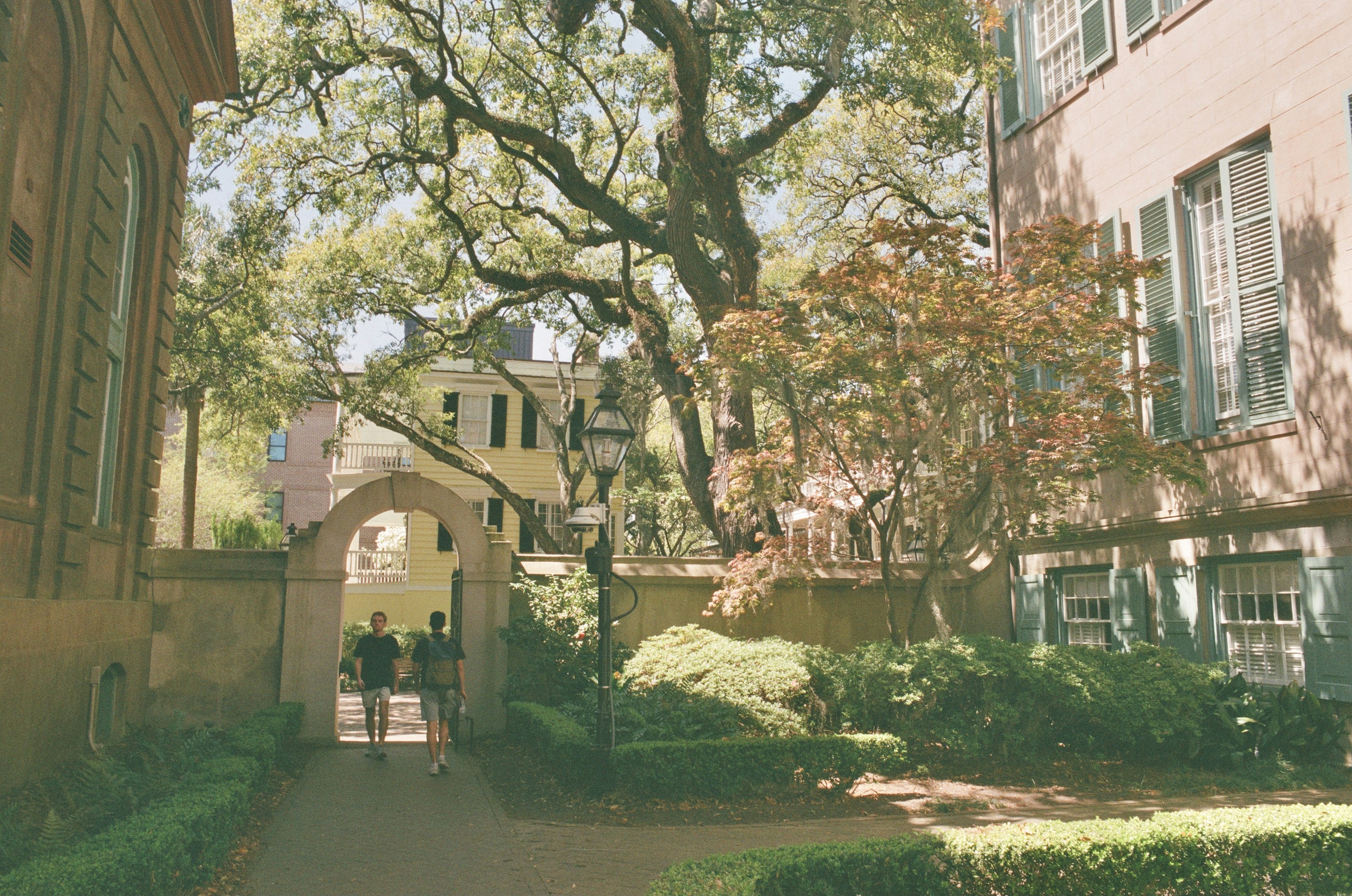 A couple of people walking through a courtyard between buildings photo ...