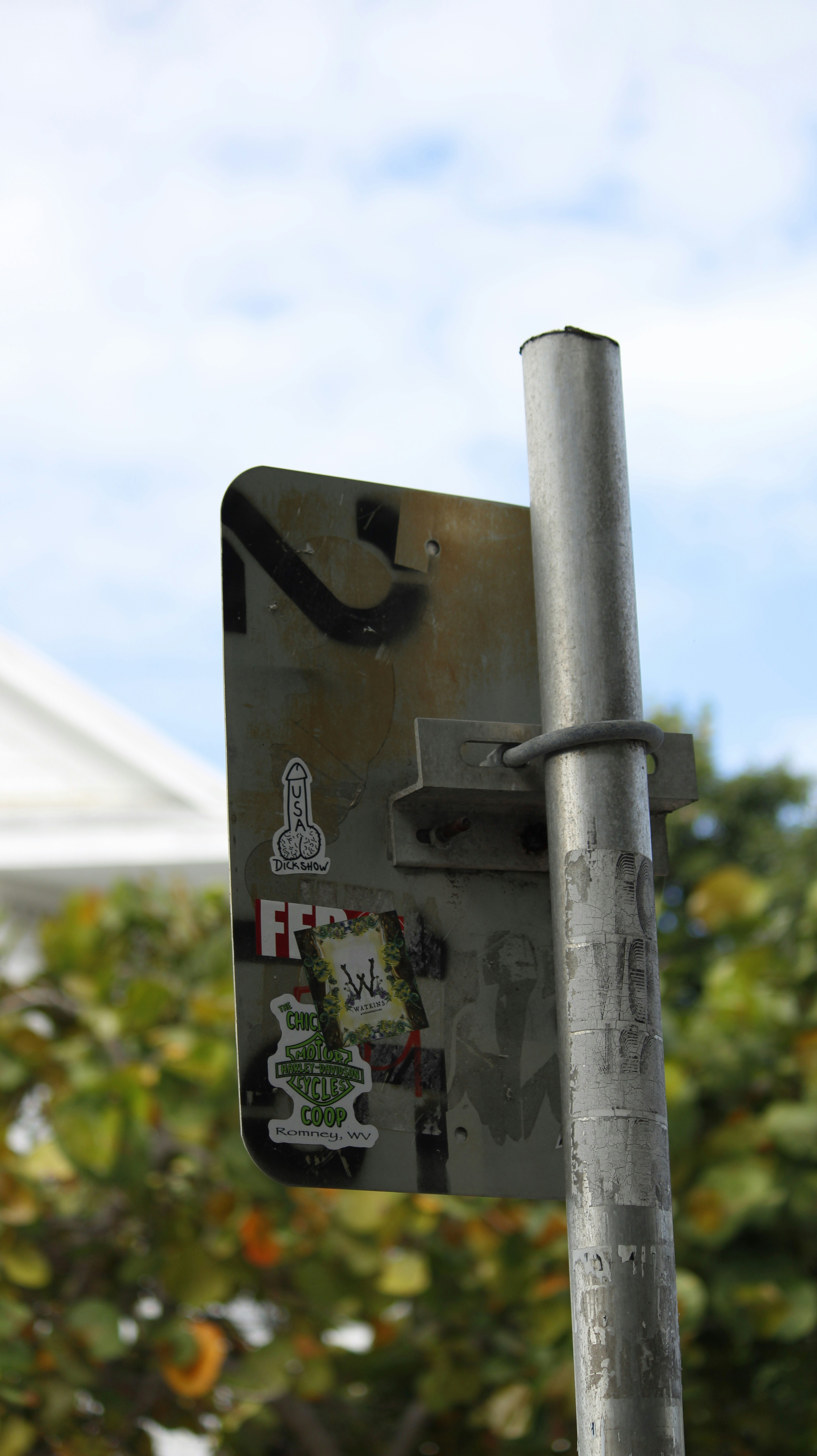 Stickered Signpost in Sharp Focus Against Blurred Suburban Backdrop