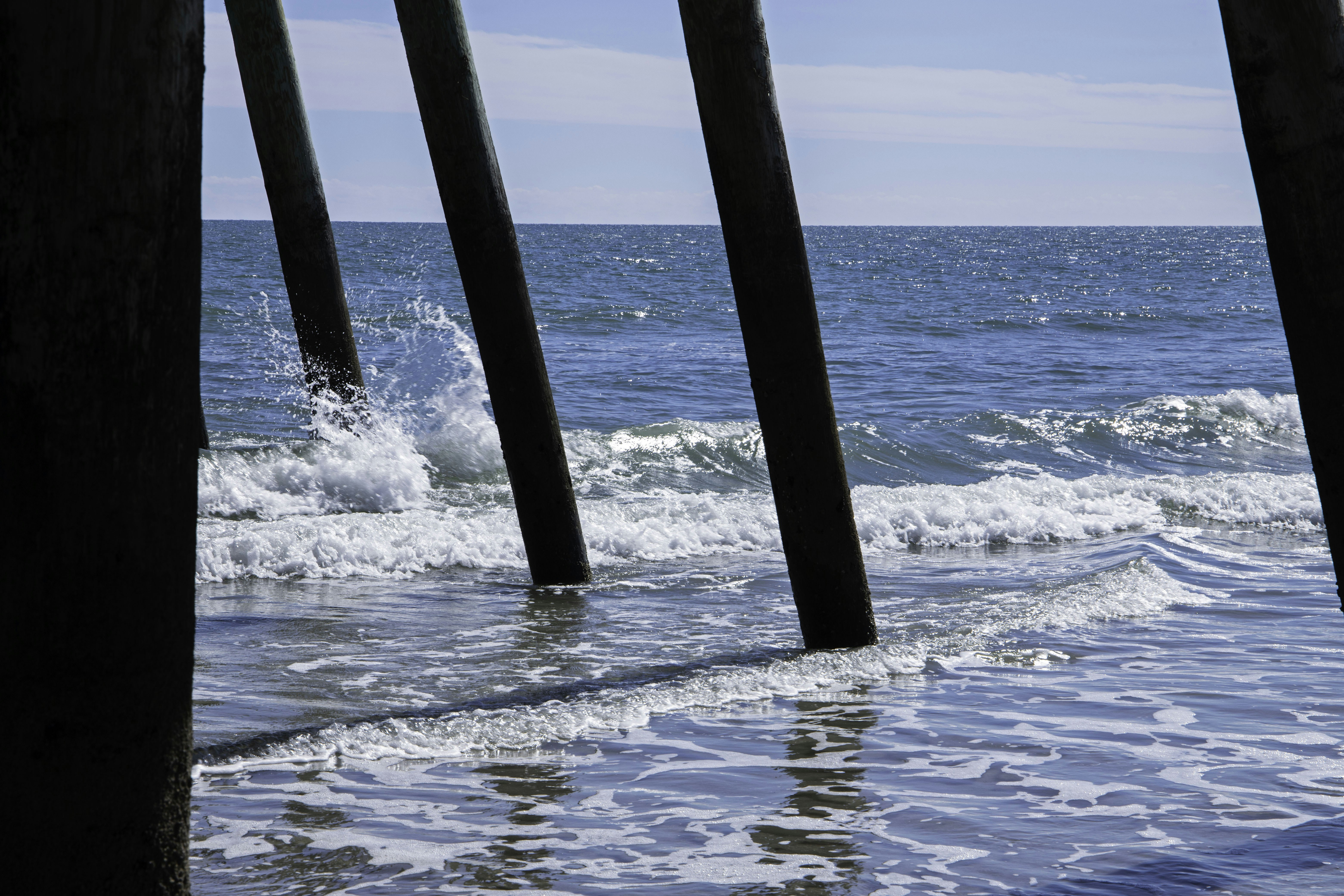 Shoreline Beams: Vertical Pier Pylons Framing a Quiet Sea