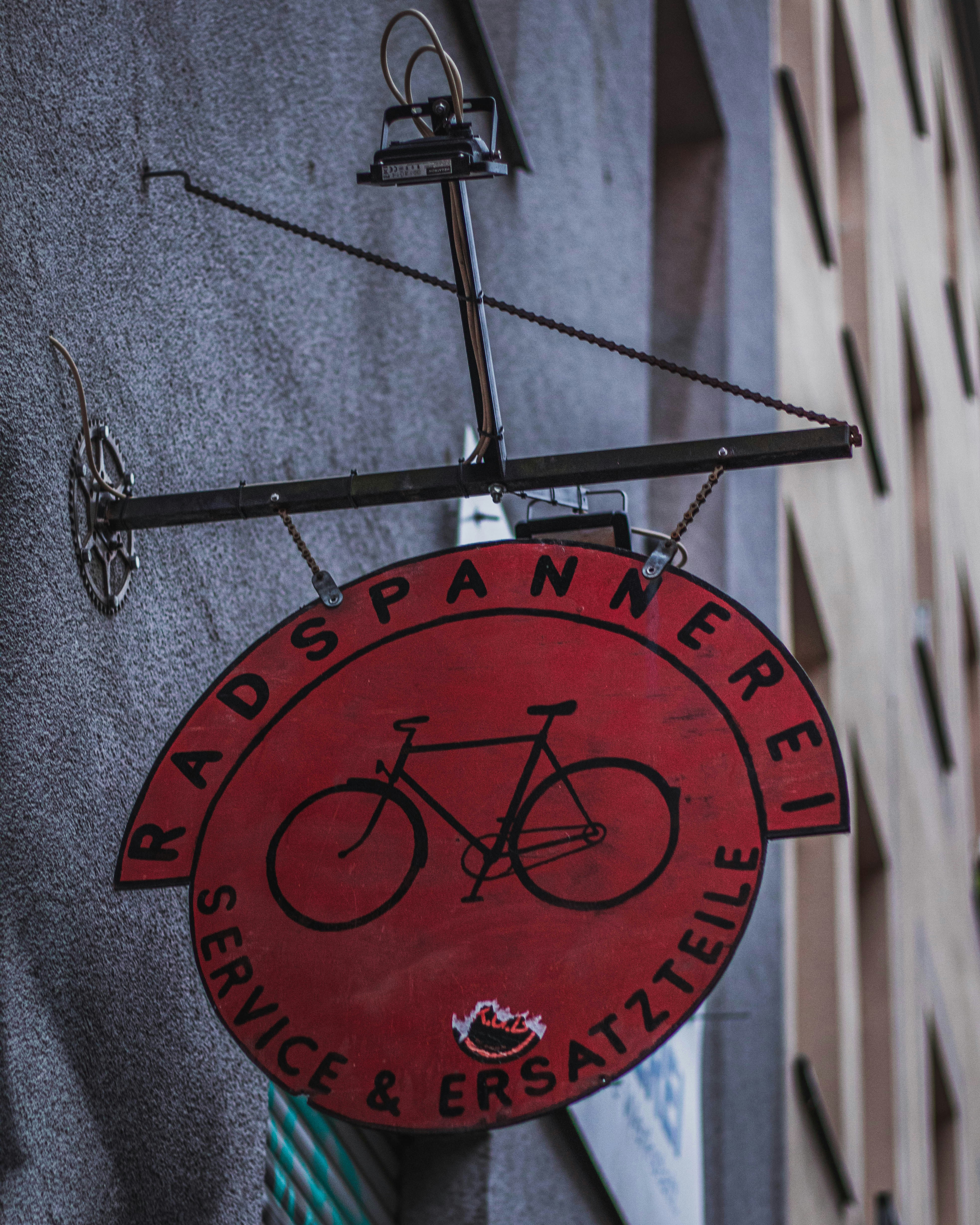 A red sign hanging from the side of a building photo – Free Urban Image ...