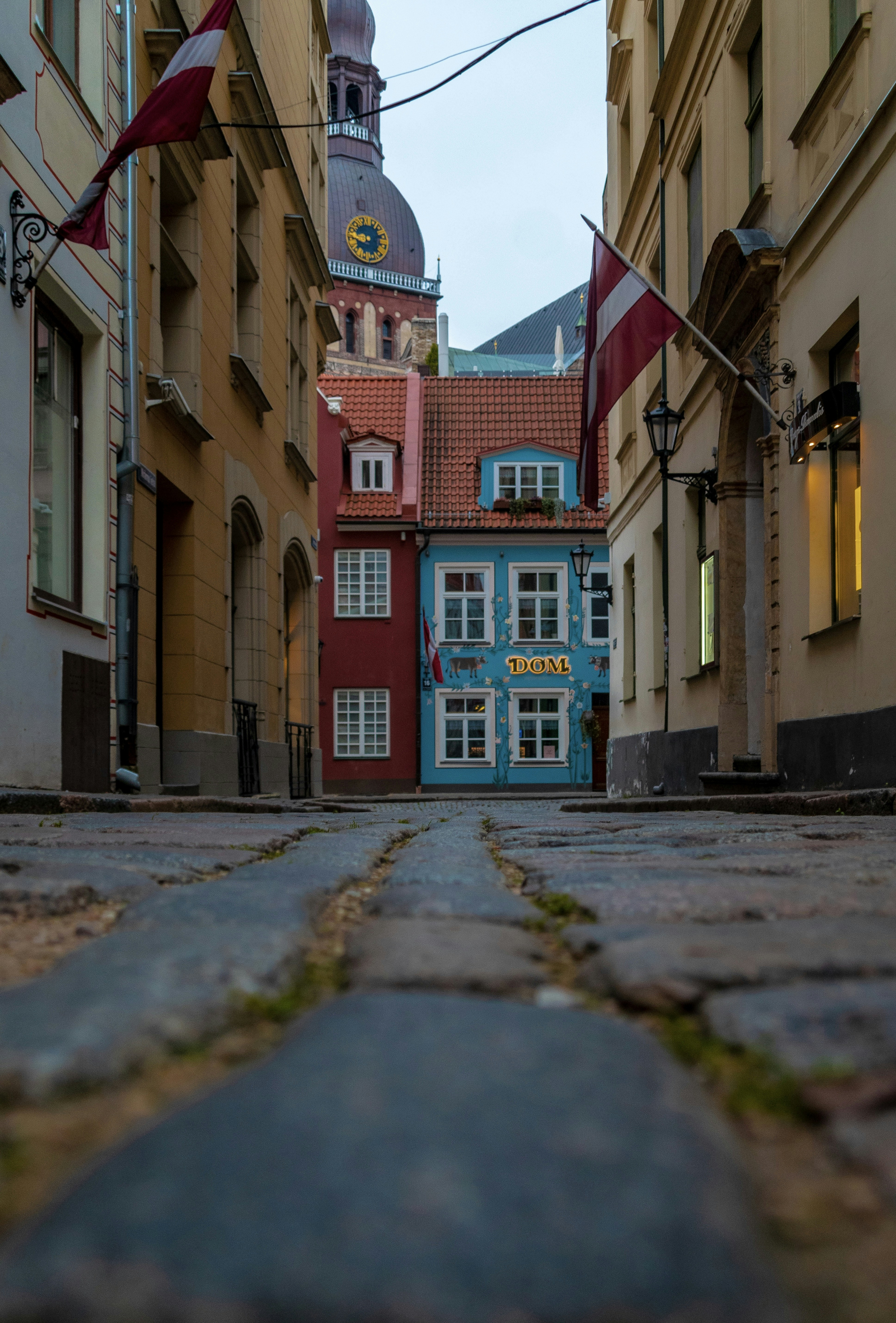 A cobblestone street with buildings and a clock tower in the background ...