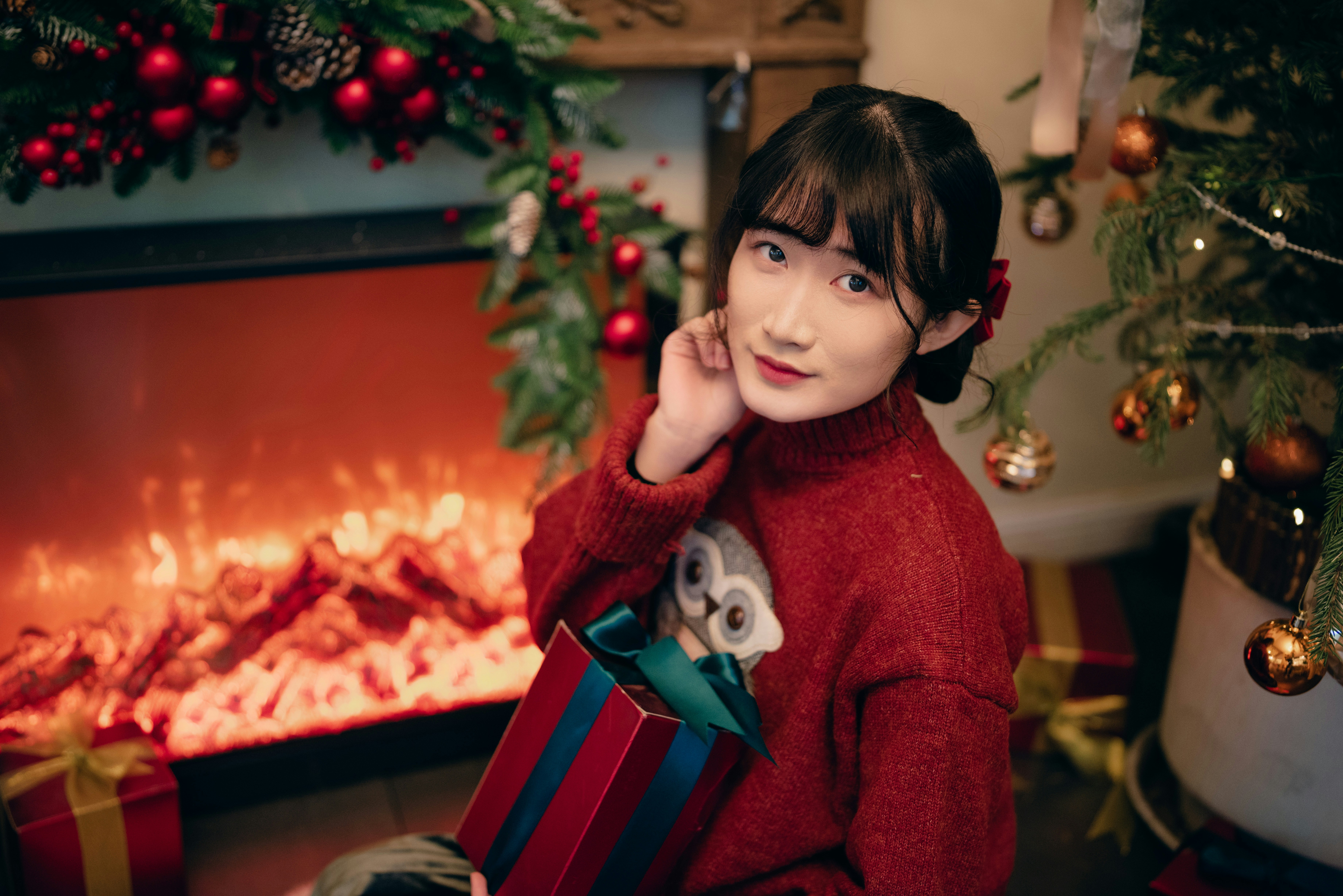 Una mujer con un suéter rojo sosteniendo un regalo de Navidad frente a ...