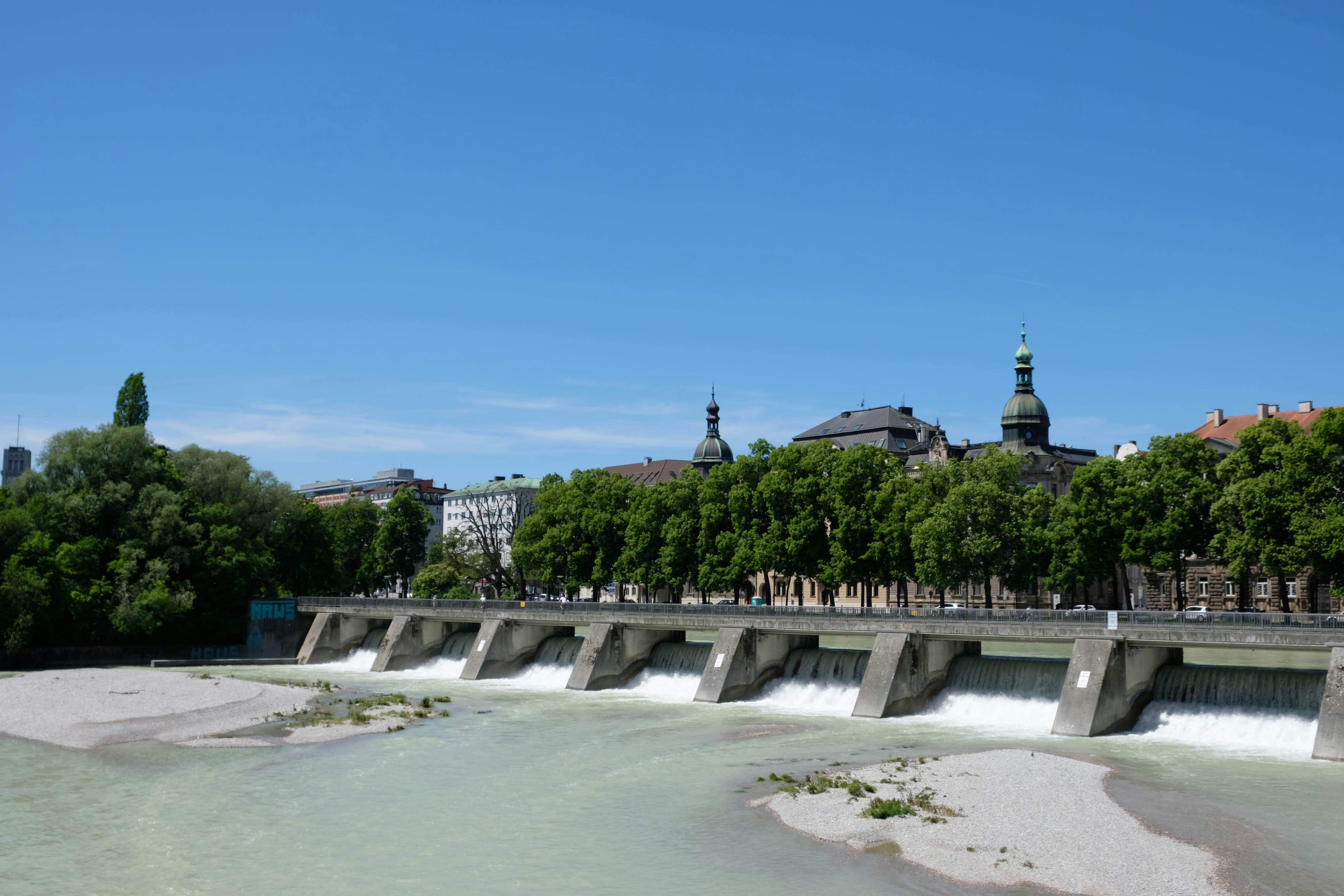 Urban Cascade: A Riverside Dam Framing a Green Skyline
