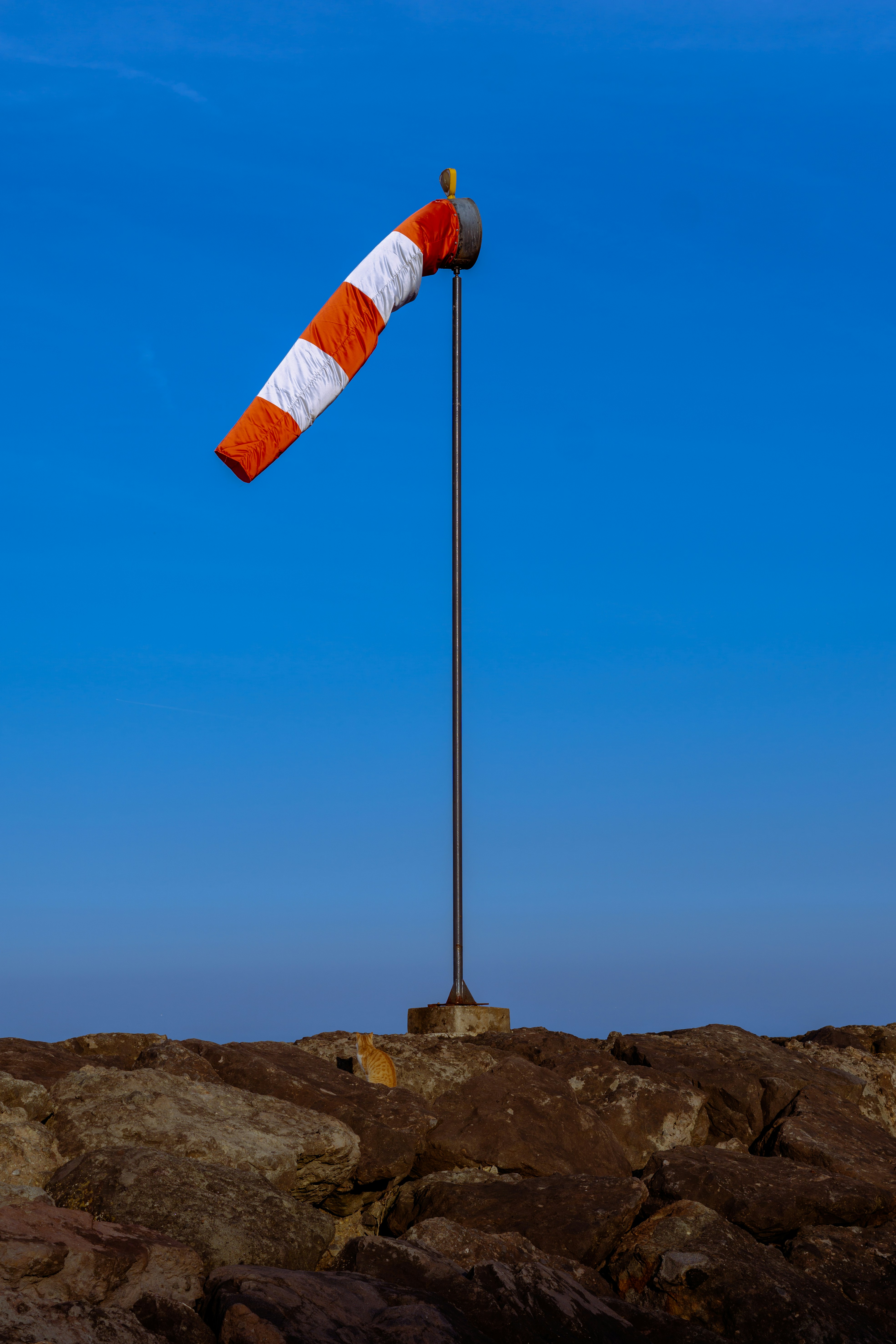 Lone Windsock on a Granite Shore Under a Cerulean Sky