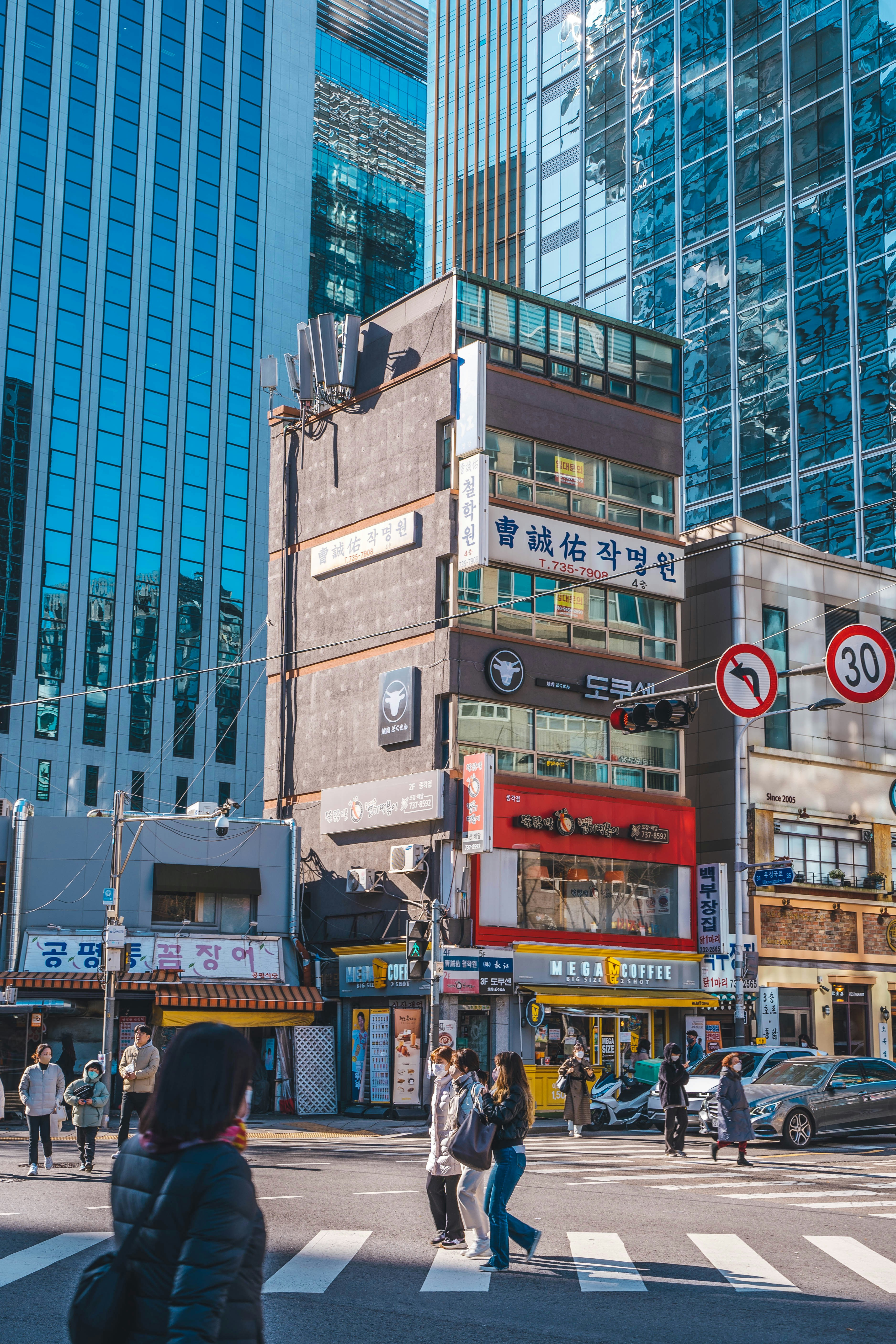 A group of people crossing a street in front of tall buildings photo ...