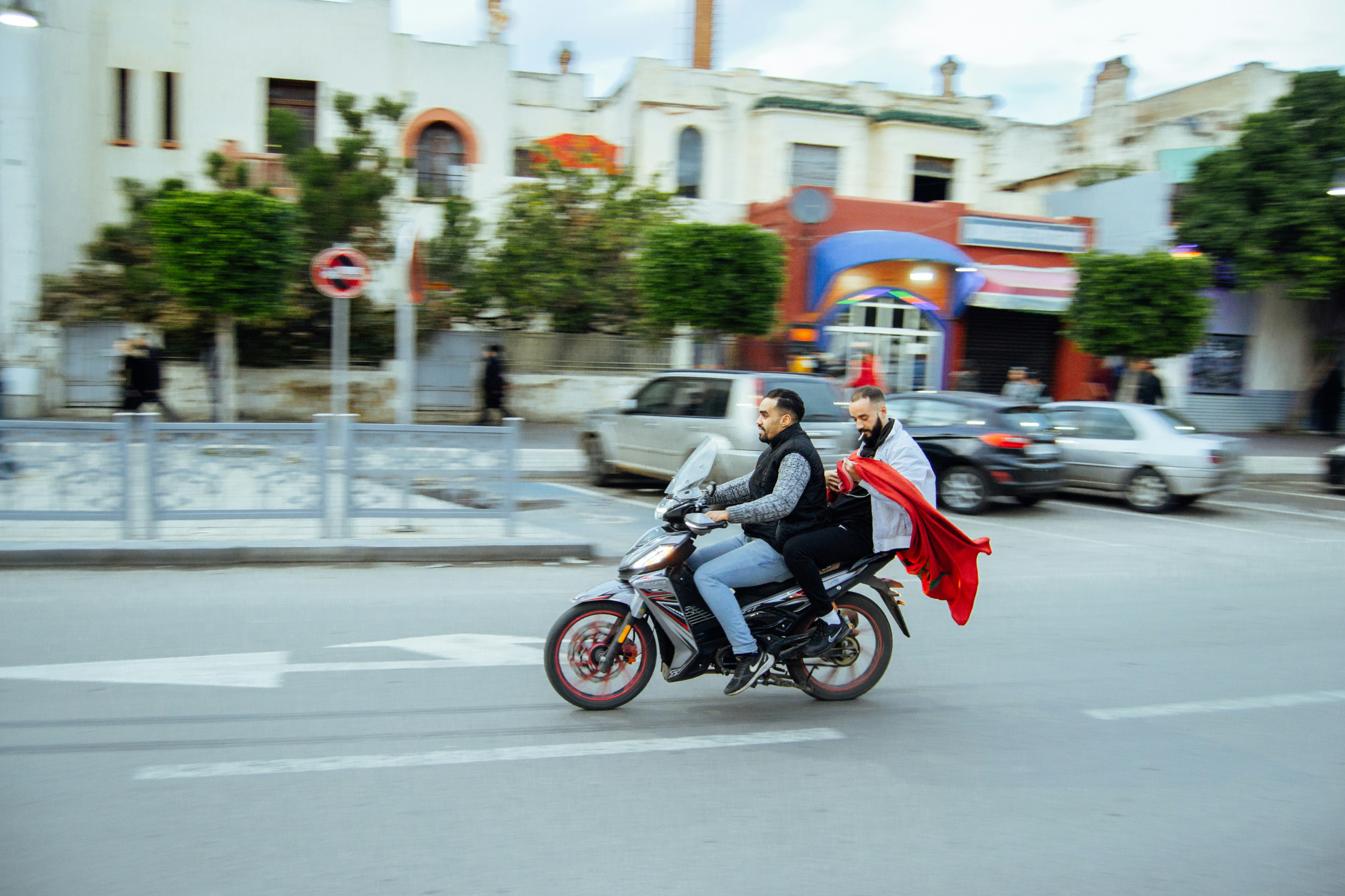 Two people riding a motorcycle on a city street photo – Free Adult ...
