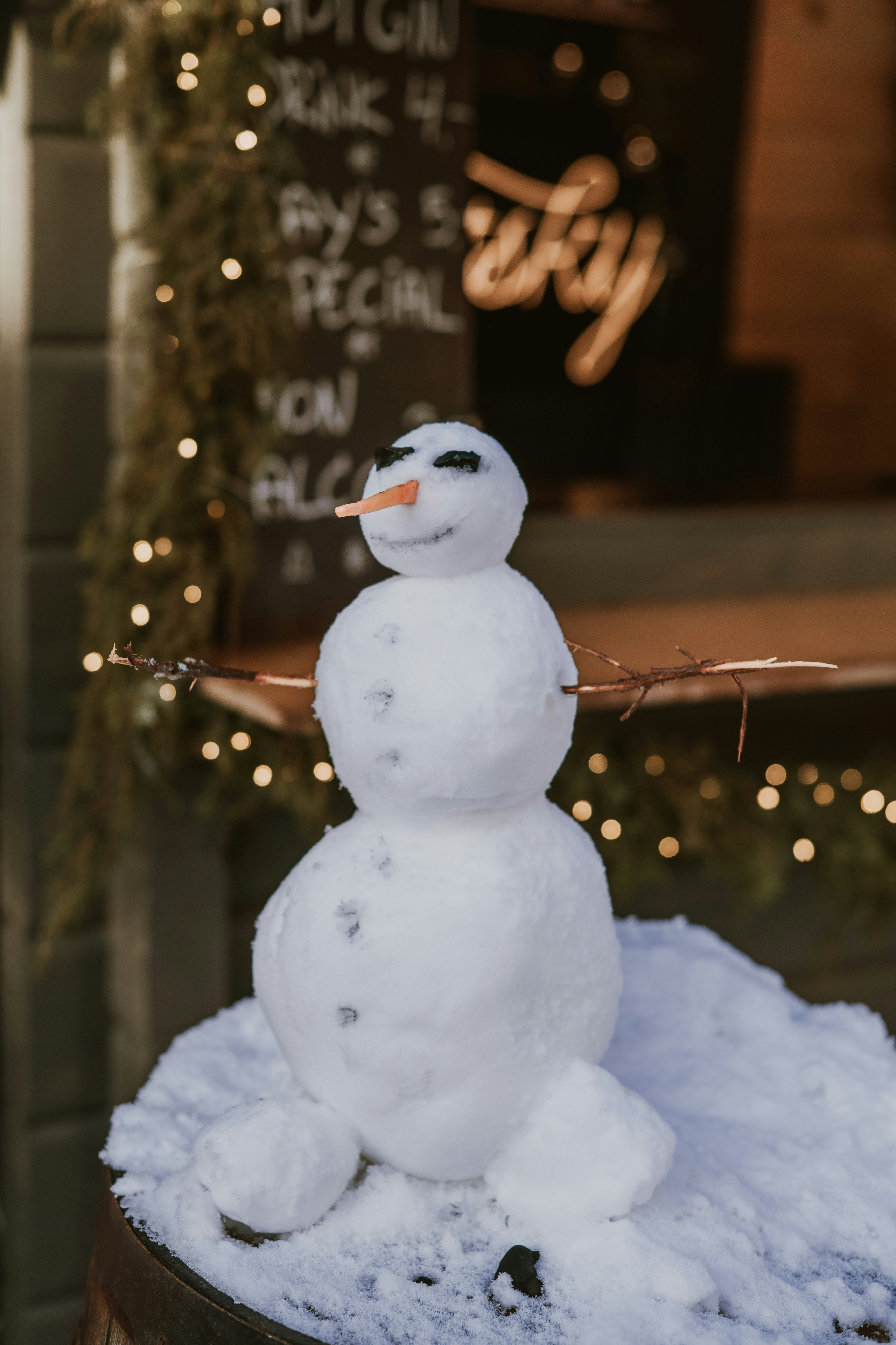 A snowman sitting on top of a barrel in the snow photo – Free Nature ...