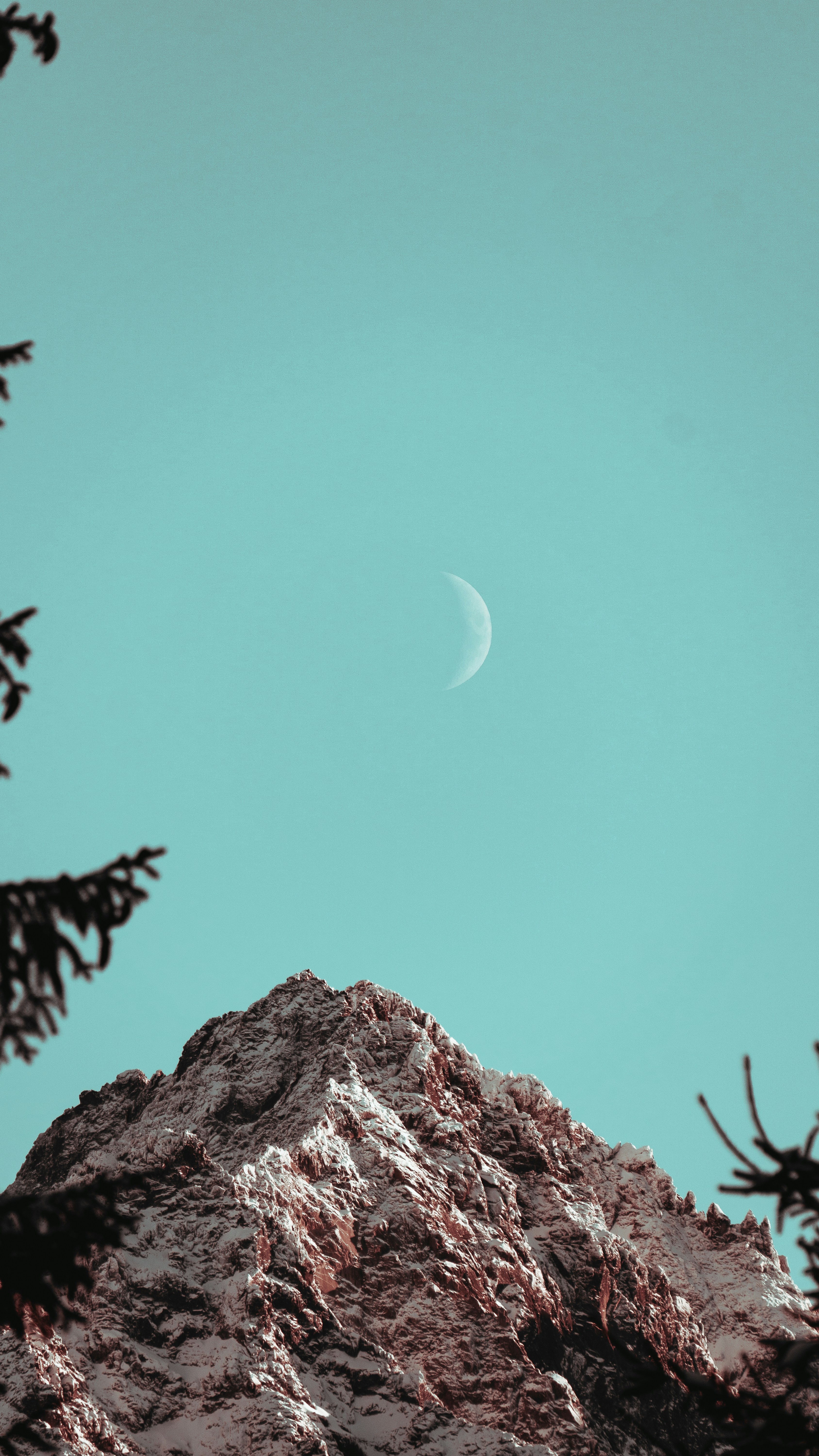 a half moon is seen above a mountain