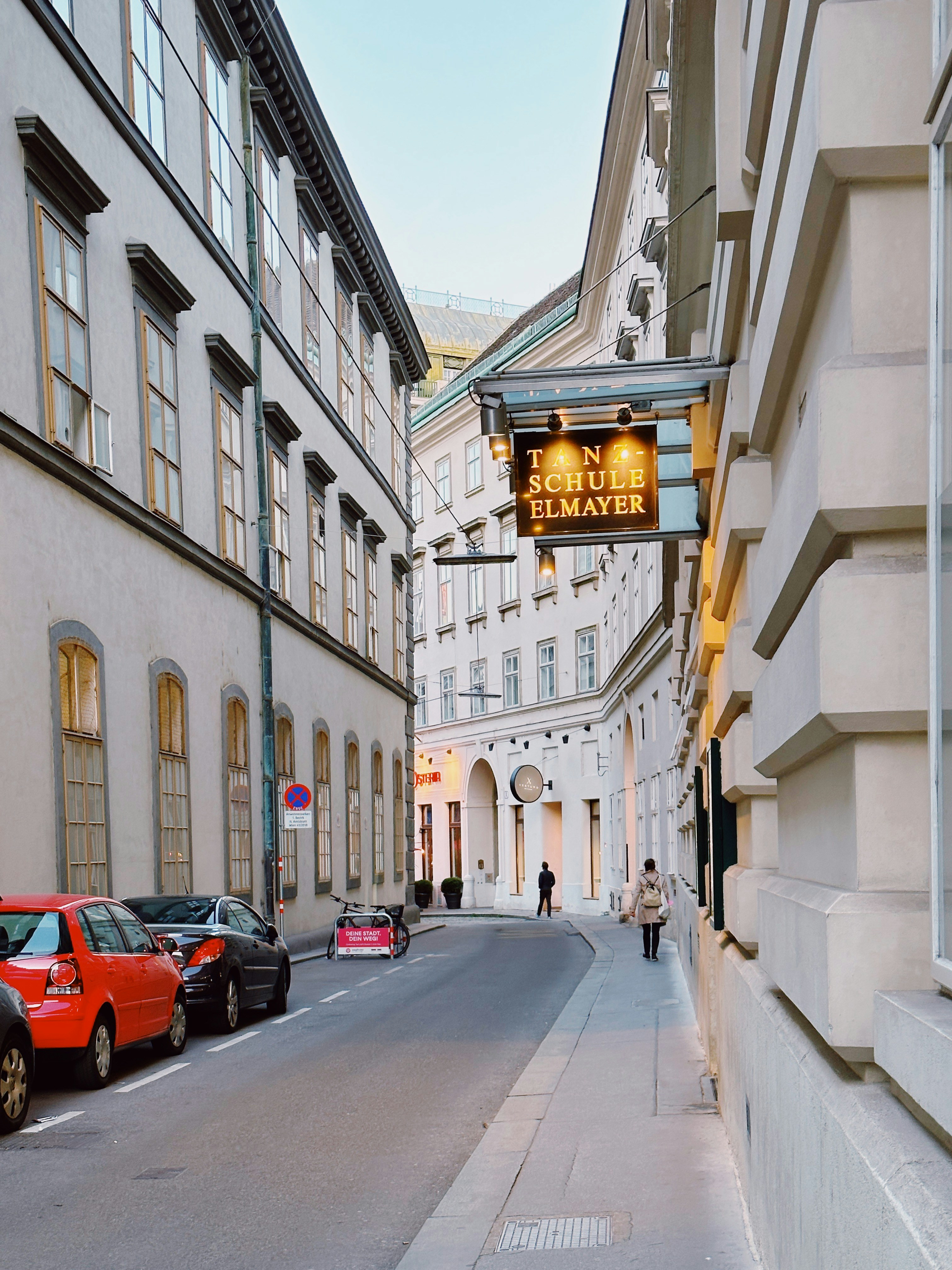 Narrow European Street Beneath a Hanging Sign