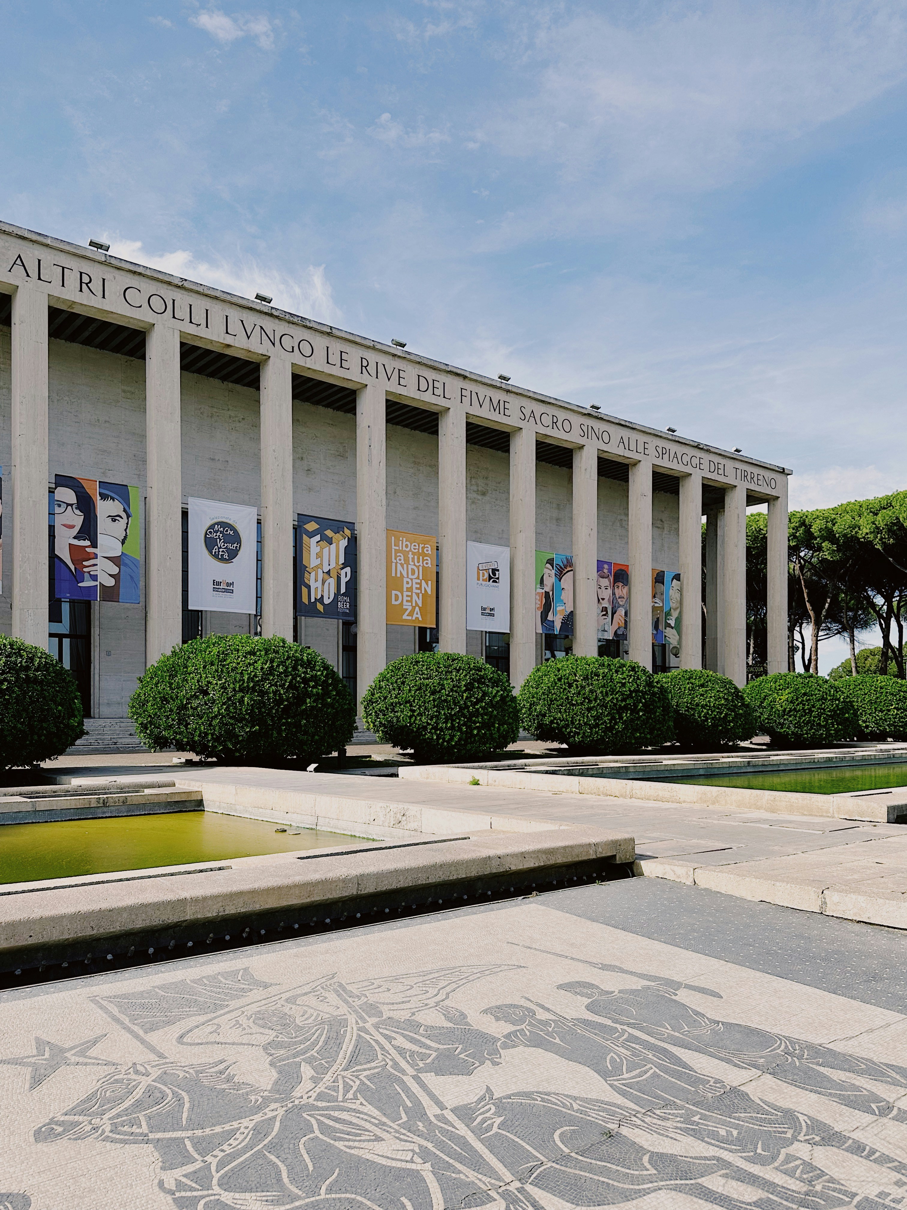 Colonnade of Color: Banners Framing a Quiet Riverside Facade