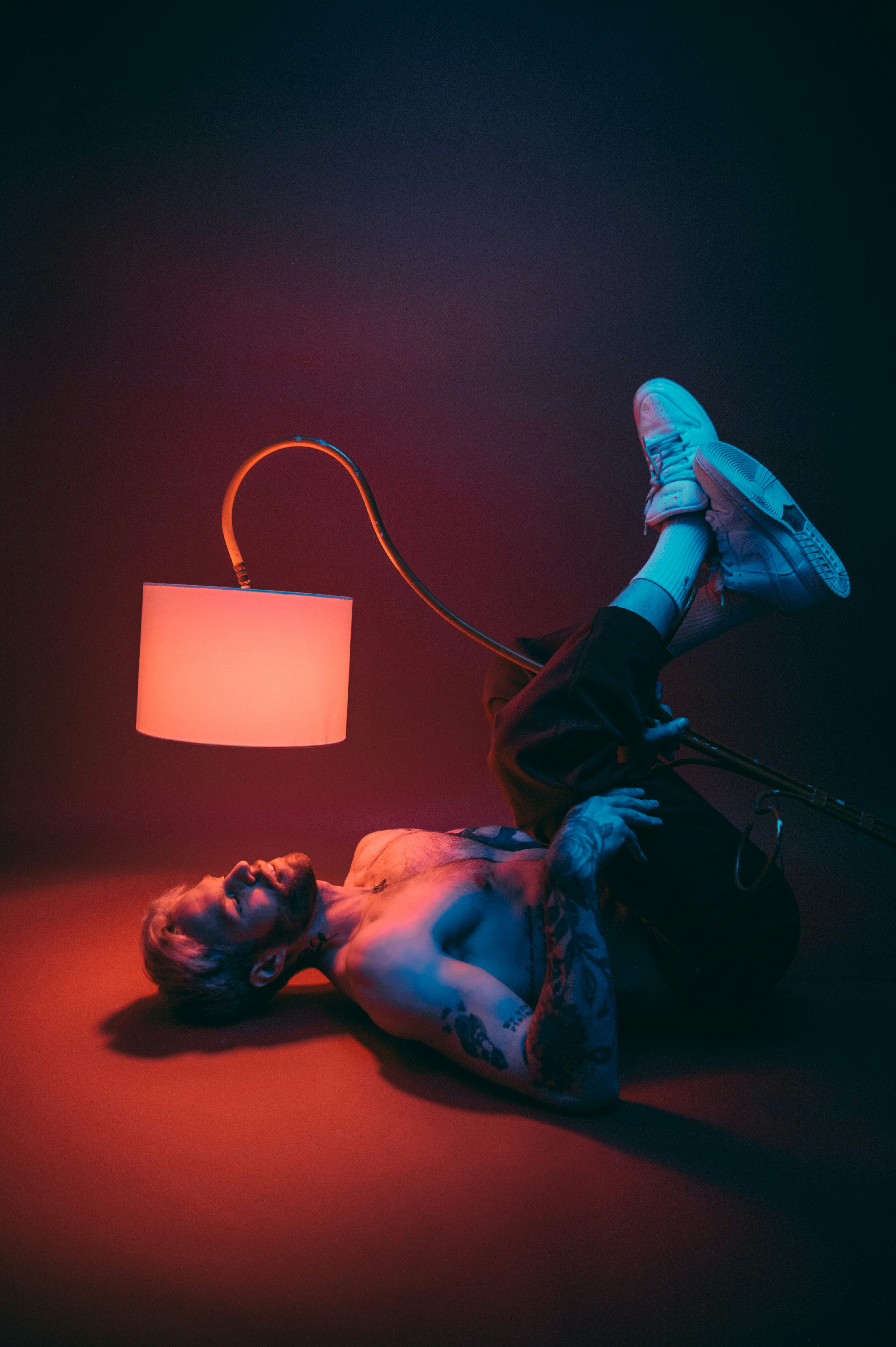 Neon Reverie on the Floor: A Lamp-lit Portrait in Red and Blue