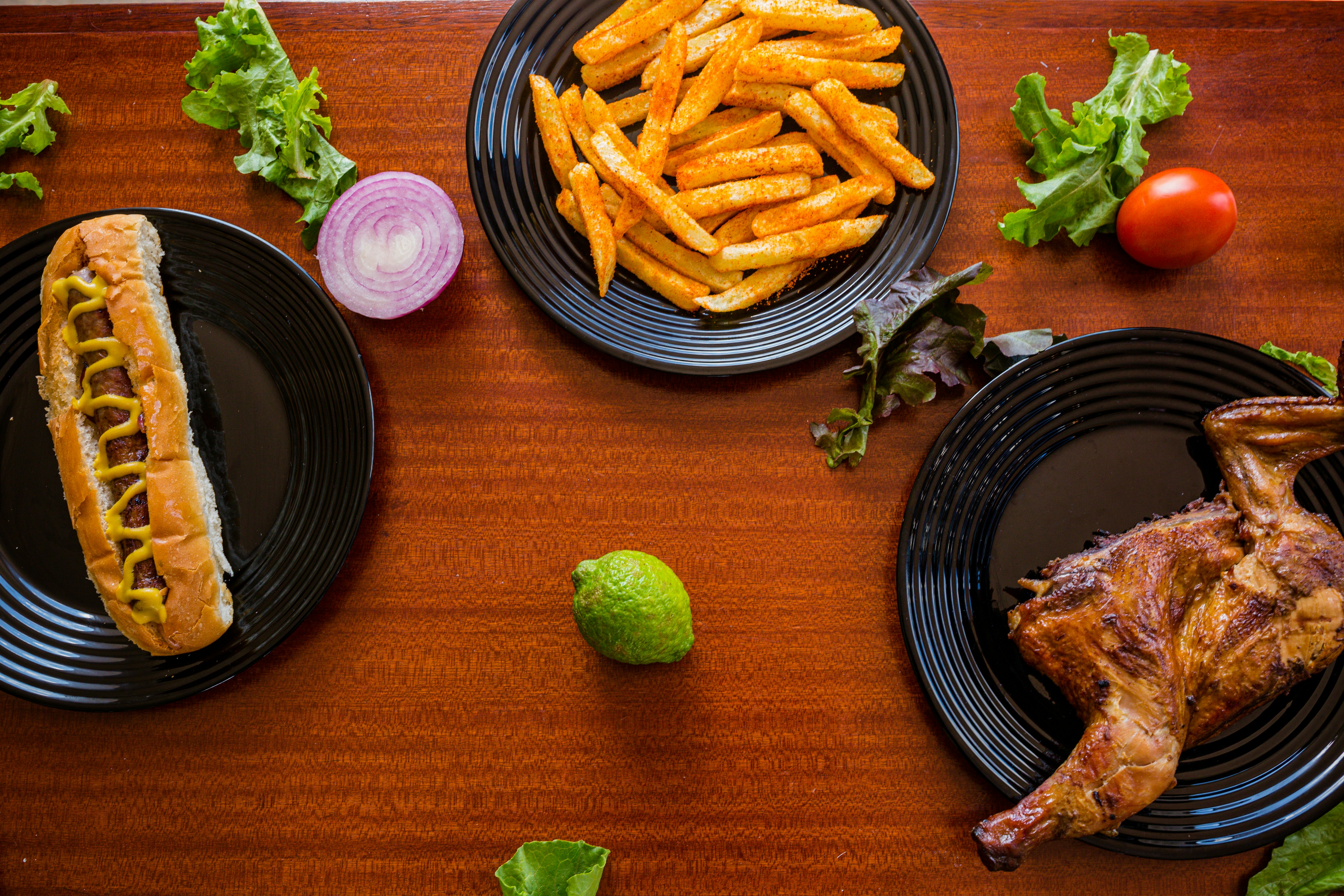A wooden table topped with black plates filled with food photo – Free ...