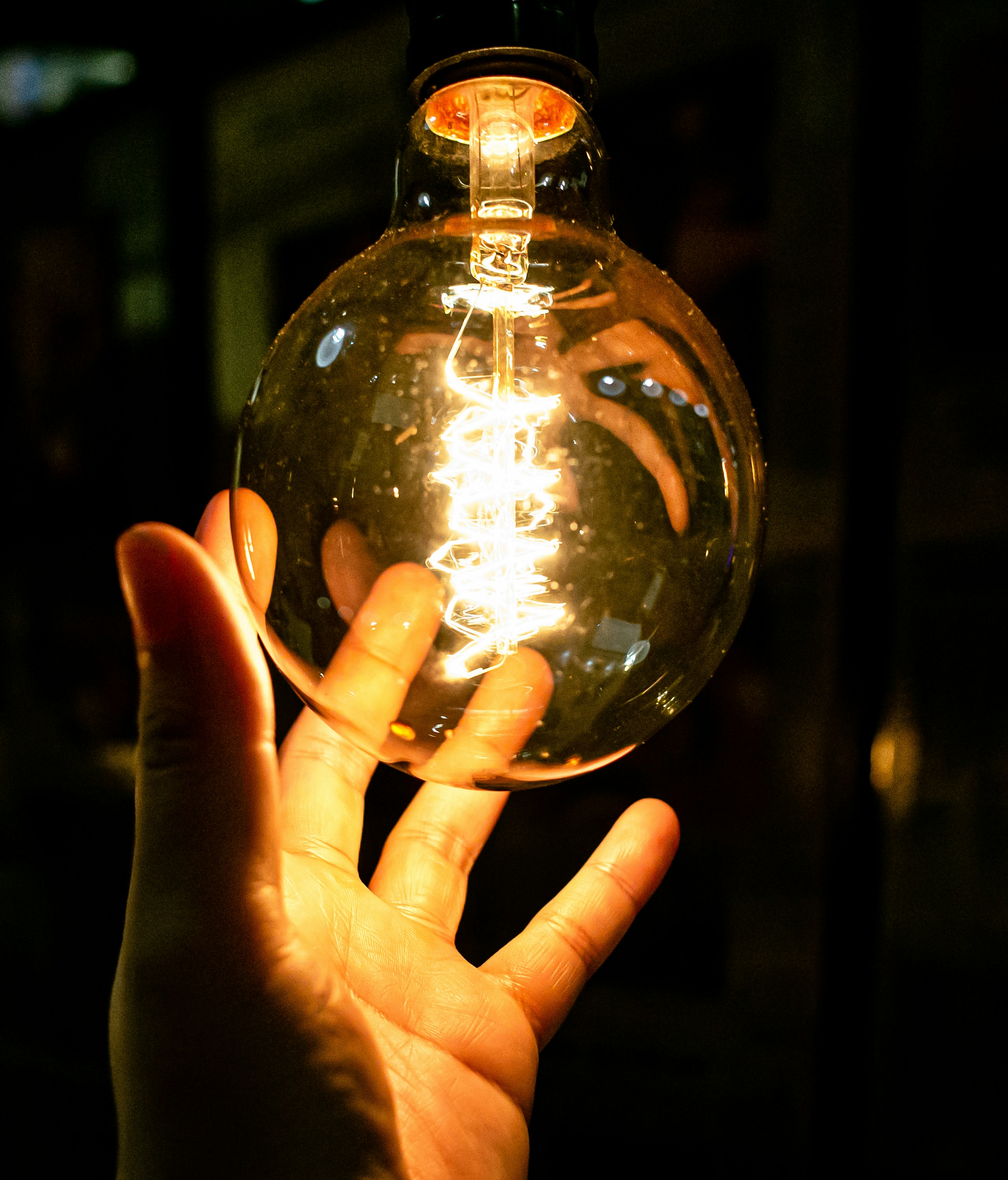 A person holding a light bulb in their hand photo – Free Electric bulb ...