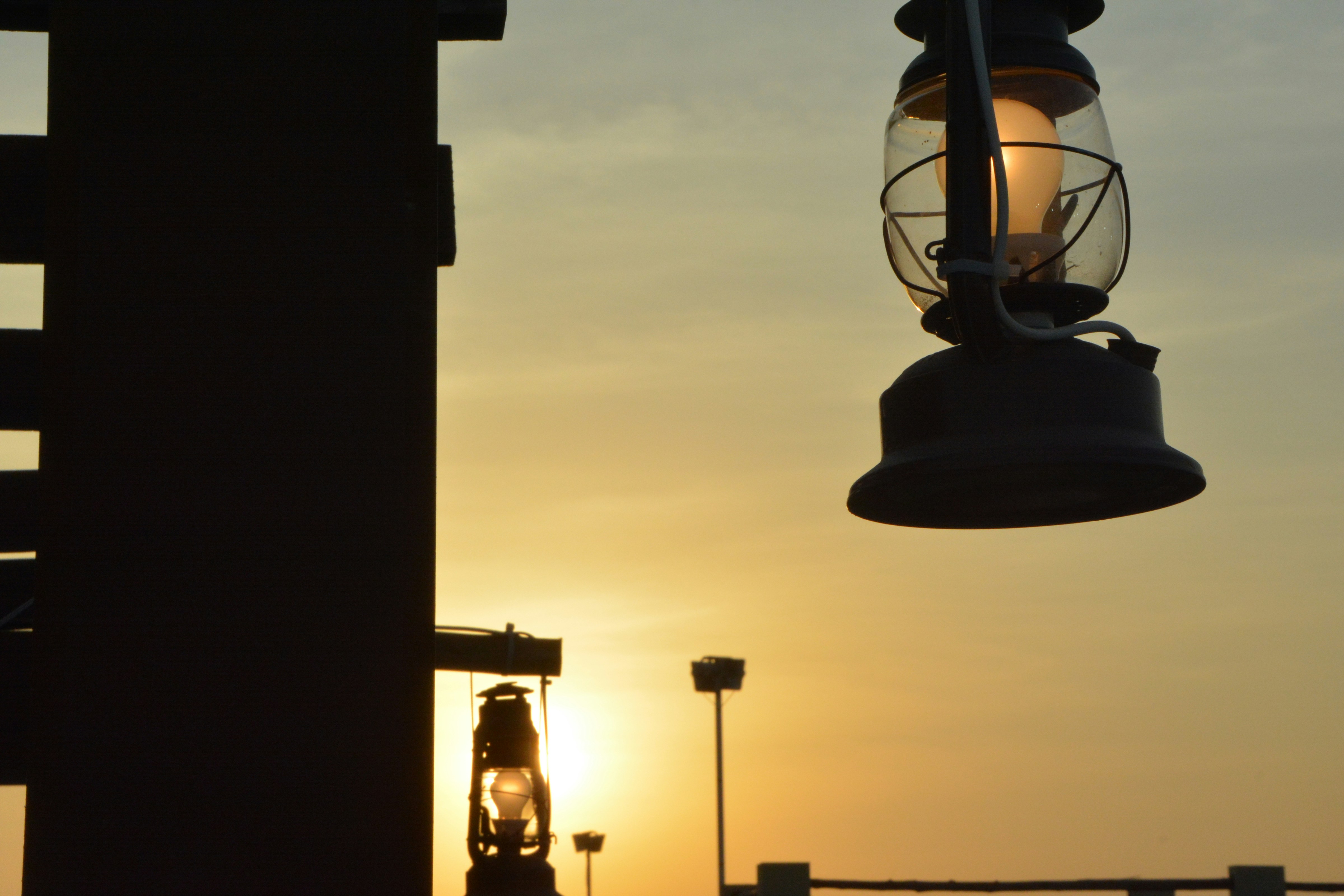 Silhouetted lanterns hang against a vibrant sunset sky.