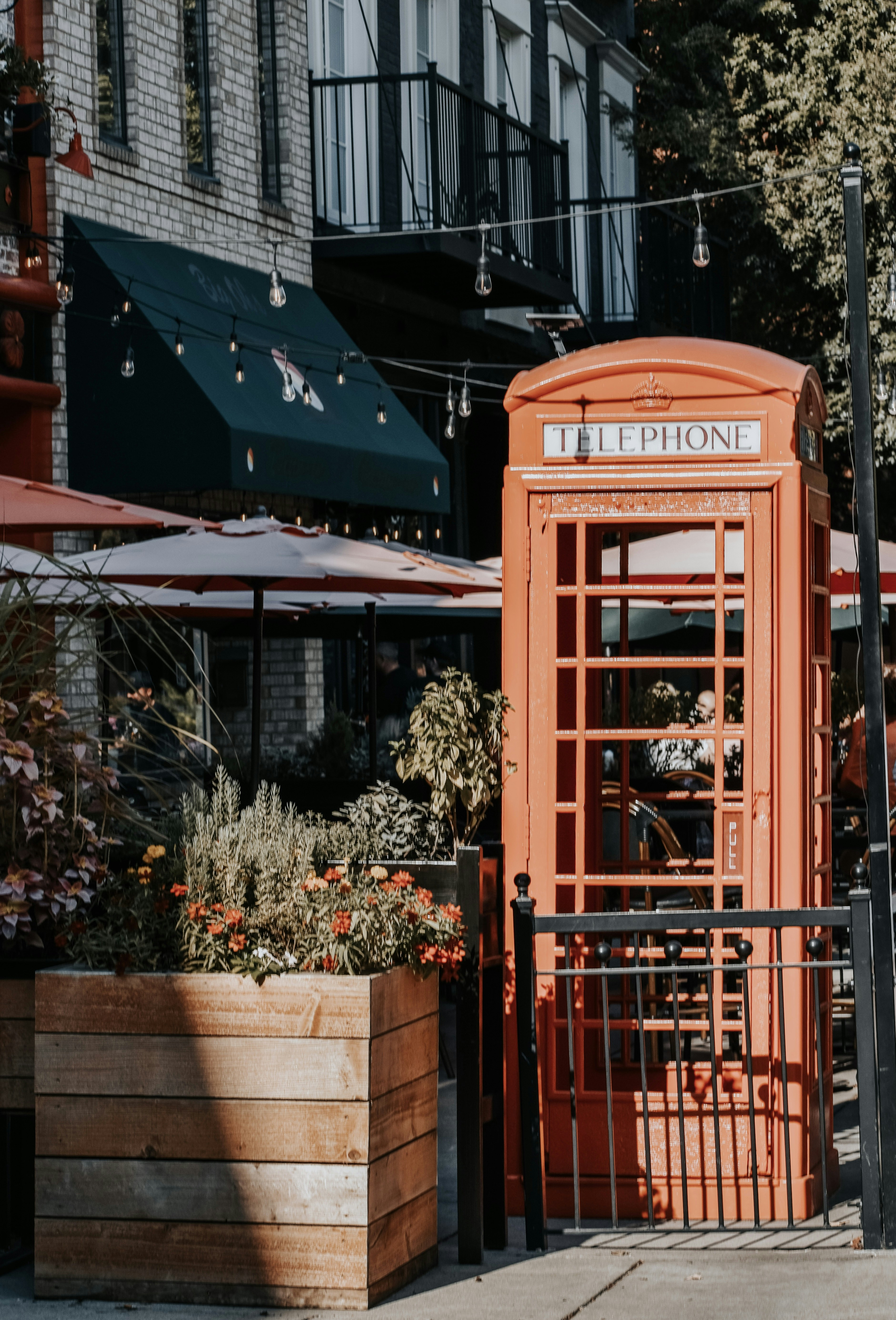 Crimson Telephone Booth Amid Lanterns and Urban Greens